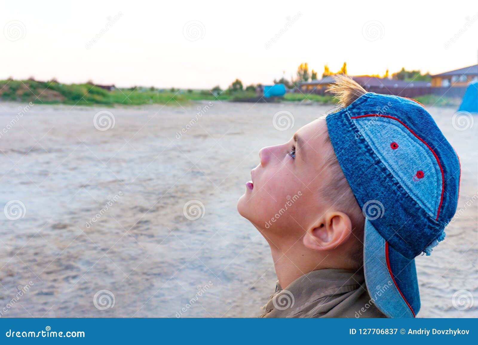 The Boy in the Blue Baseball Cap at the Evening Sunset Looks Up. Stock ...