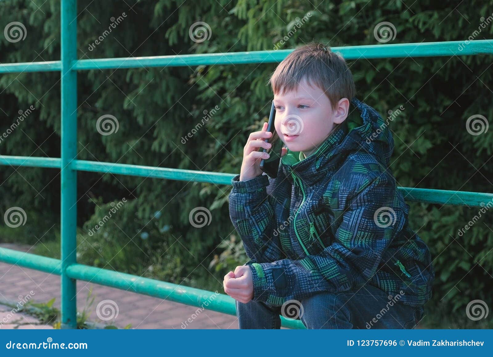 Boy Calls on the Phone and Talking Sitting in the Park. Stock Photo ...