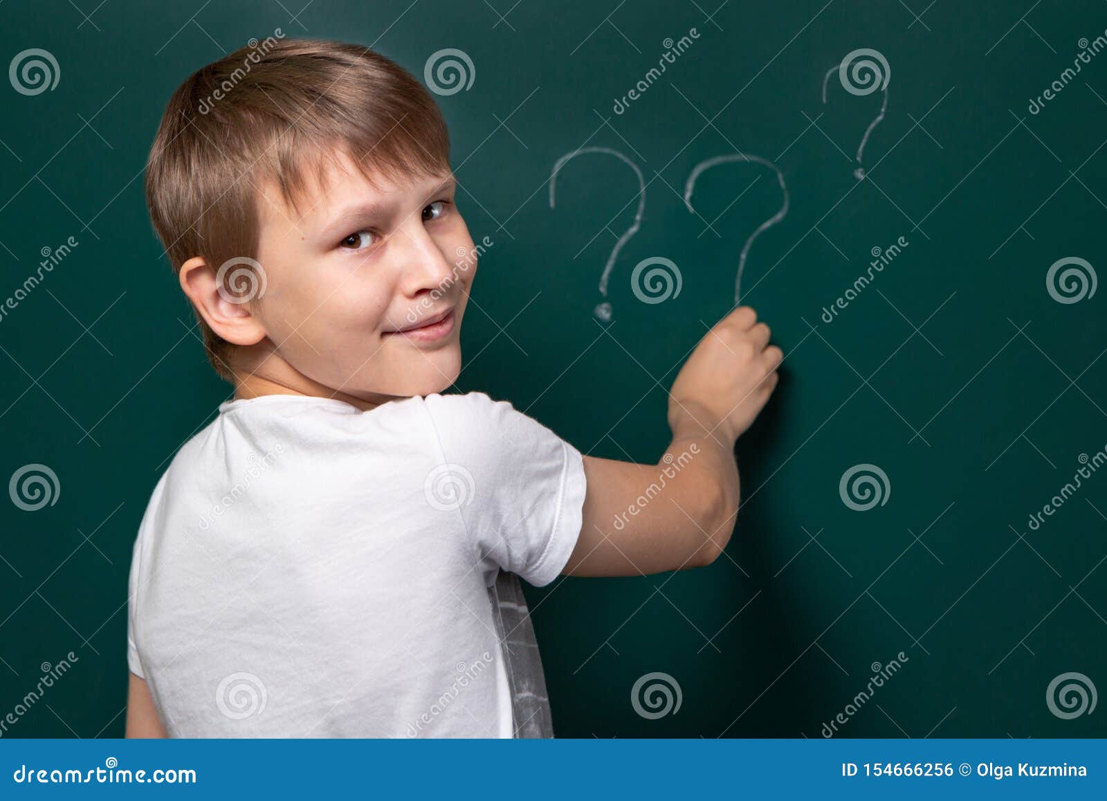 A Boy of Caucasian Appearance Writes a Question Mark on the Chalkboard ...