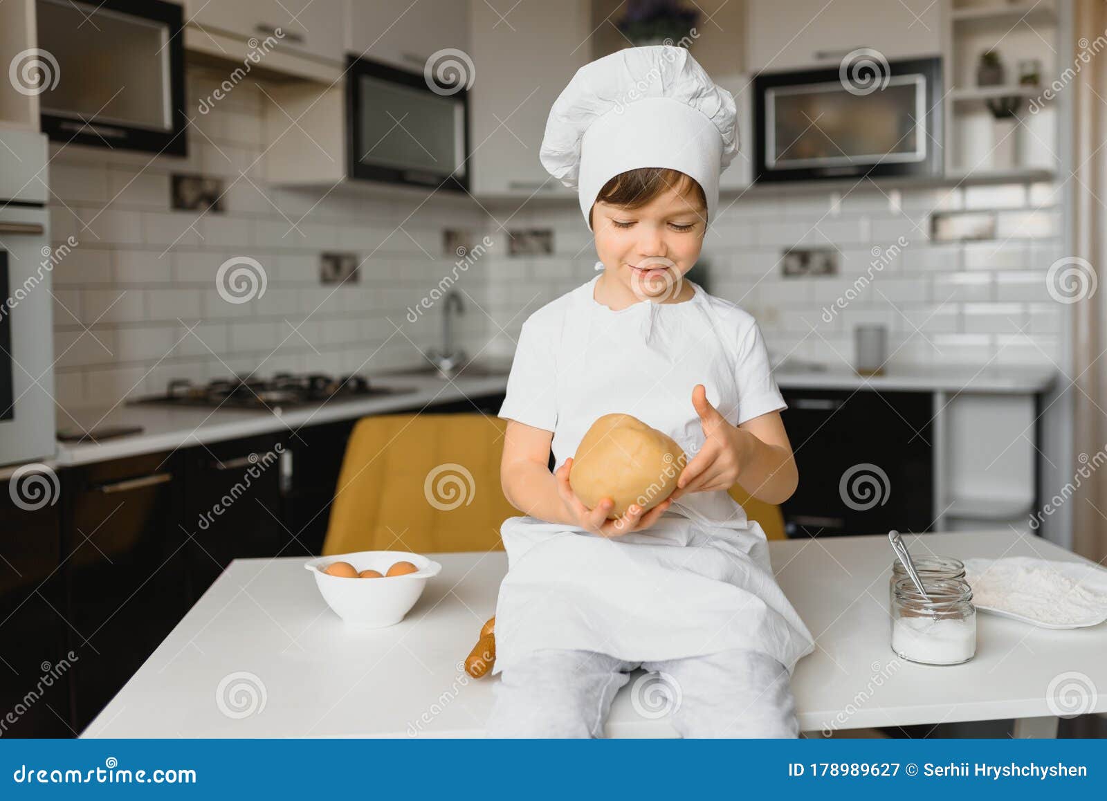 Boy in Cook Hat Sitting at a Kitchen Counter. Little Boy in Kitchen ...