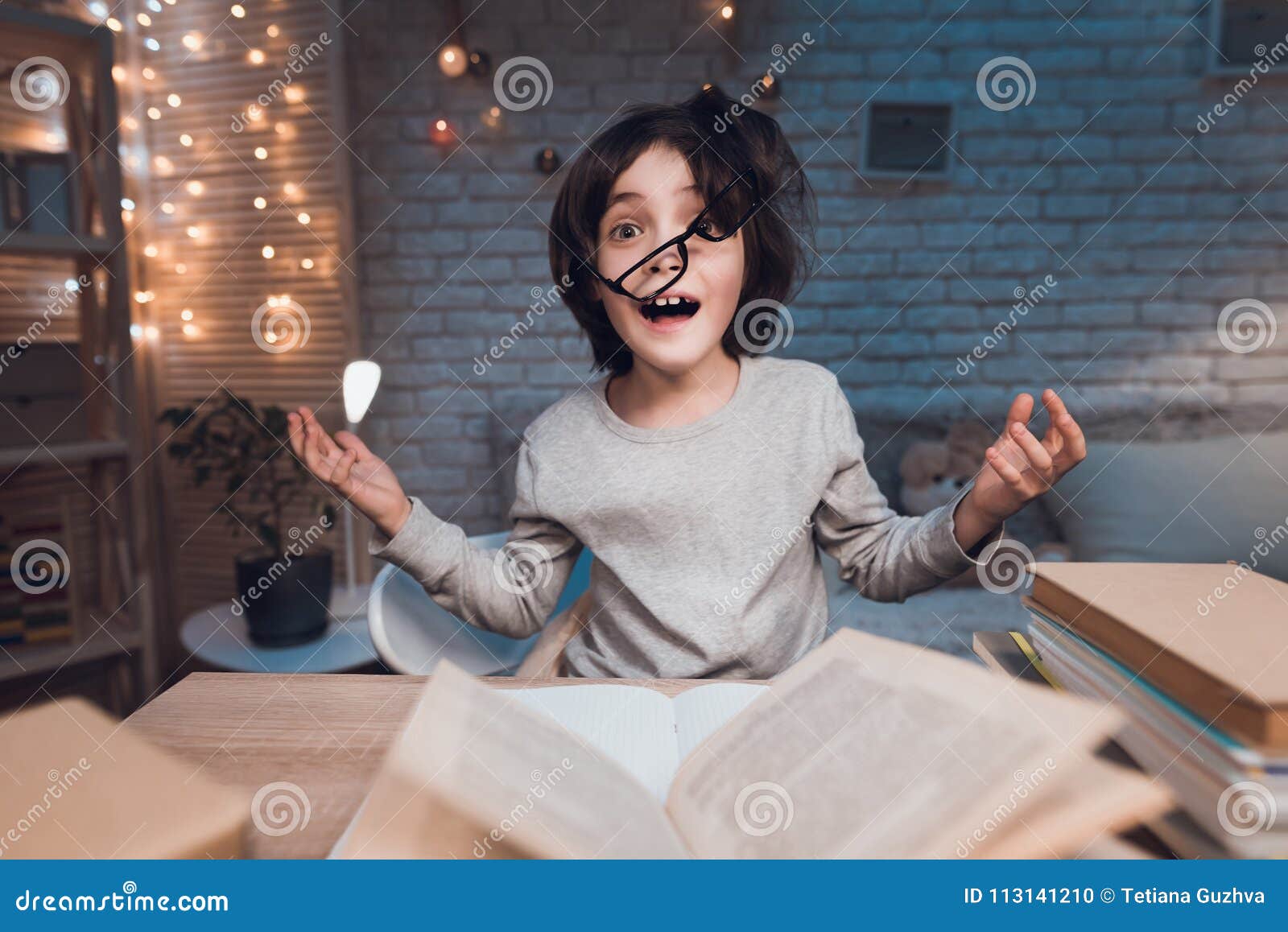 Boy is Doing Homework for School Surrounded by Books at Night at Home ...