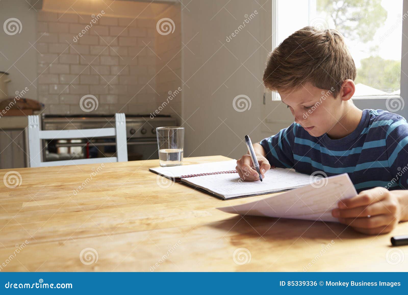 Boy Doing Homework Sitting at Kitchen Table Stock Photo - Image of ...