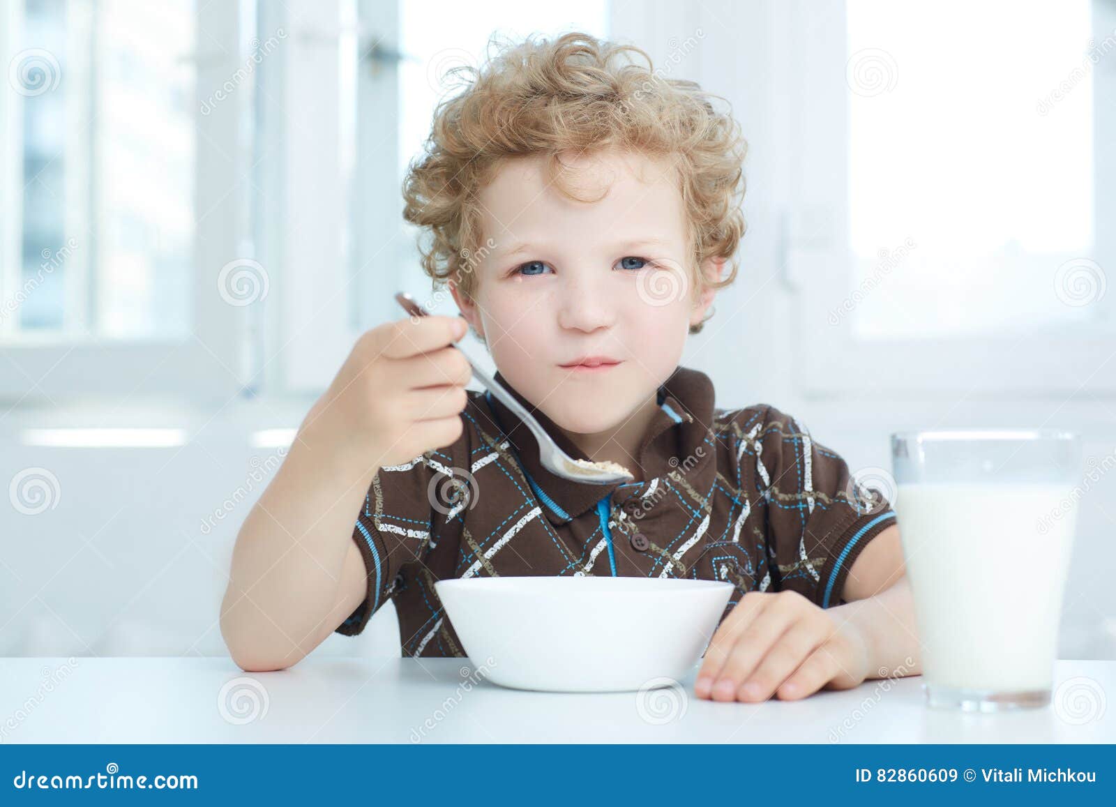Curly Boy Eating Cereal while Having Breakfast in the Kitchen. Stock ...