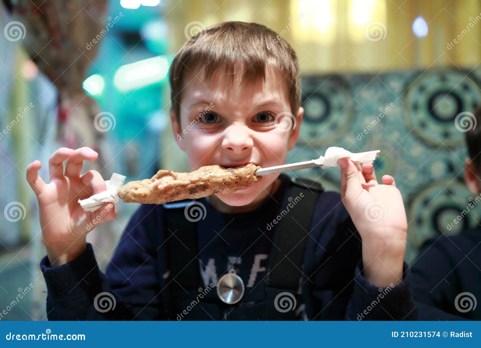 Boy eating kebab on skewer stock photo. Image of dining - 210231574