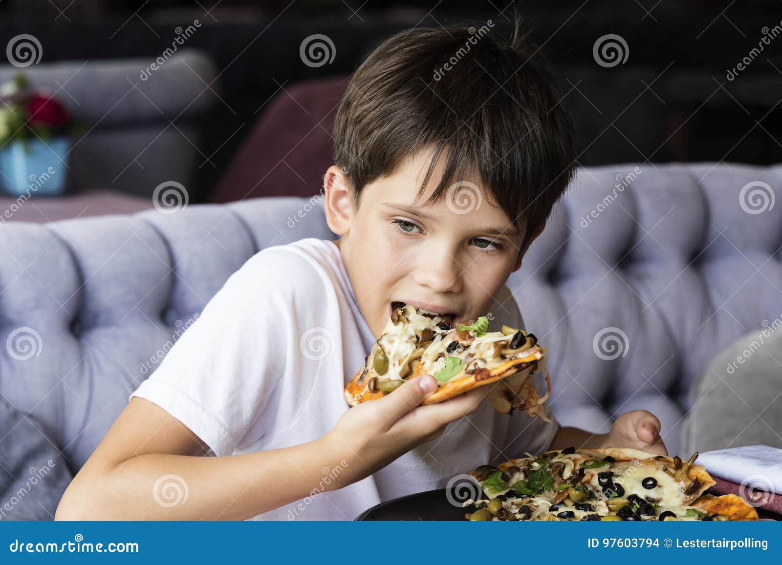 The boy is eating pizza stock photo. Image of portion - 97603794