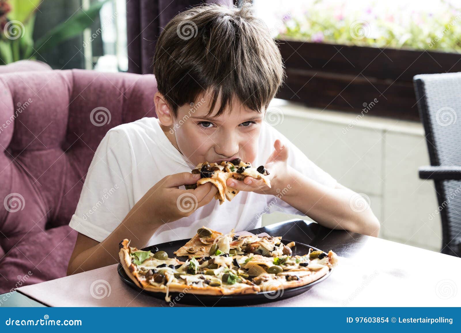 The boy is eating pizza stock photo. Image of restaurant - 97603854