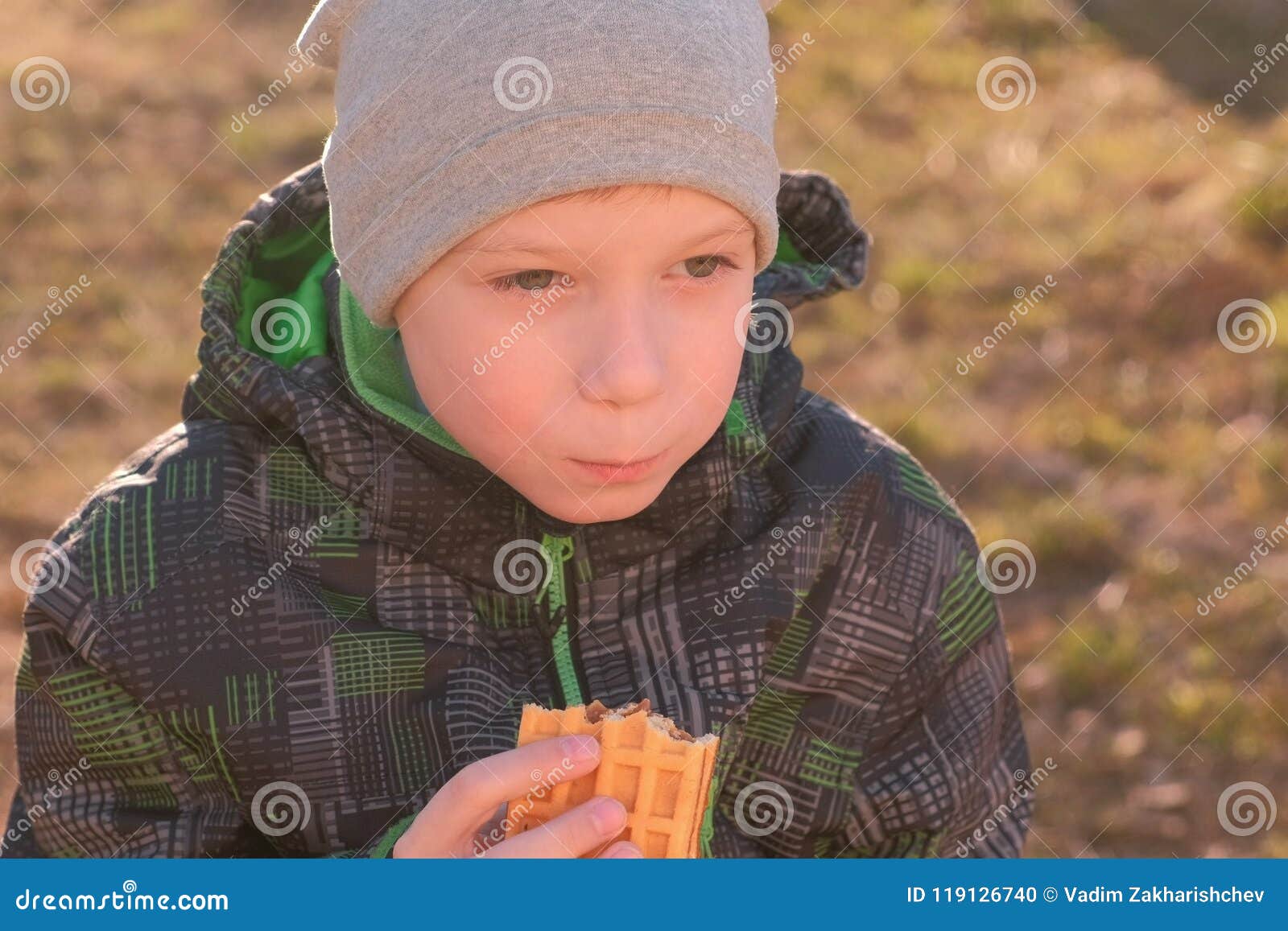Boy Eats Waffles Sitting on the Bench in Park. Front View. Stock Photo ...