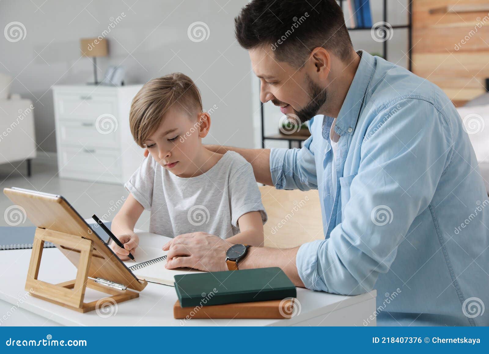 Boy With Father Doing Homework Using Tablet At Table In Room Royalty ...