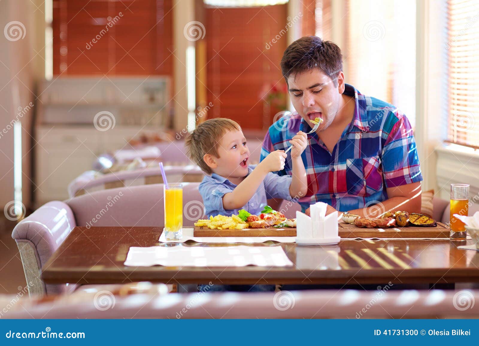 Boy Feeding Father in Restaurant Stock Photo - Image of cafe, happy ...