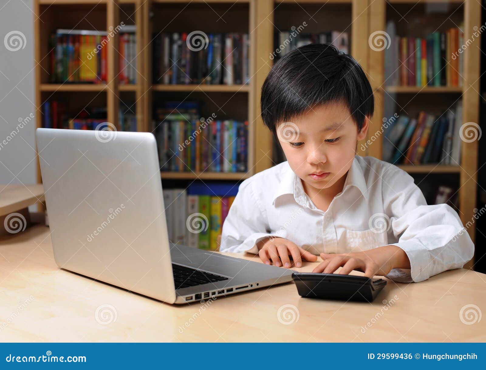 A Boy in Front of Laptop Computer and Making Calculations on Calculator ...