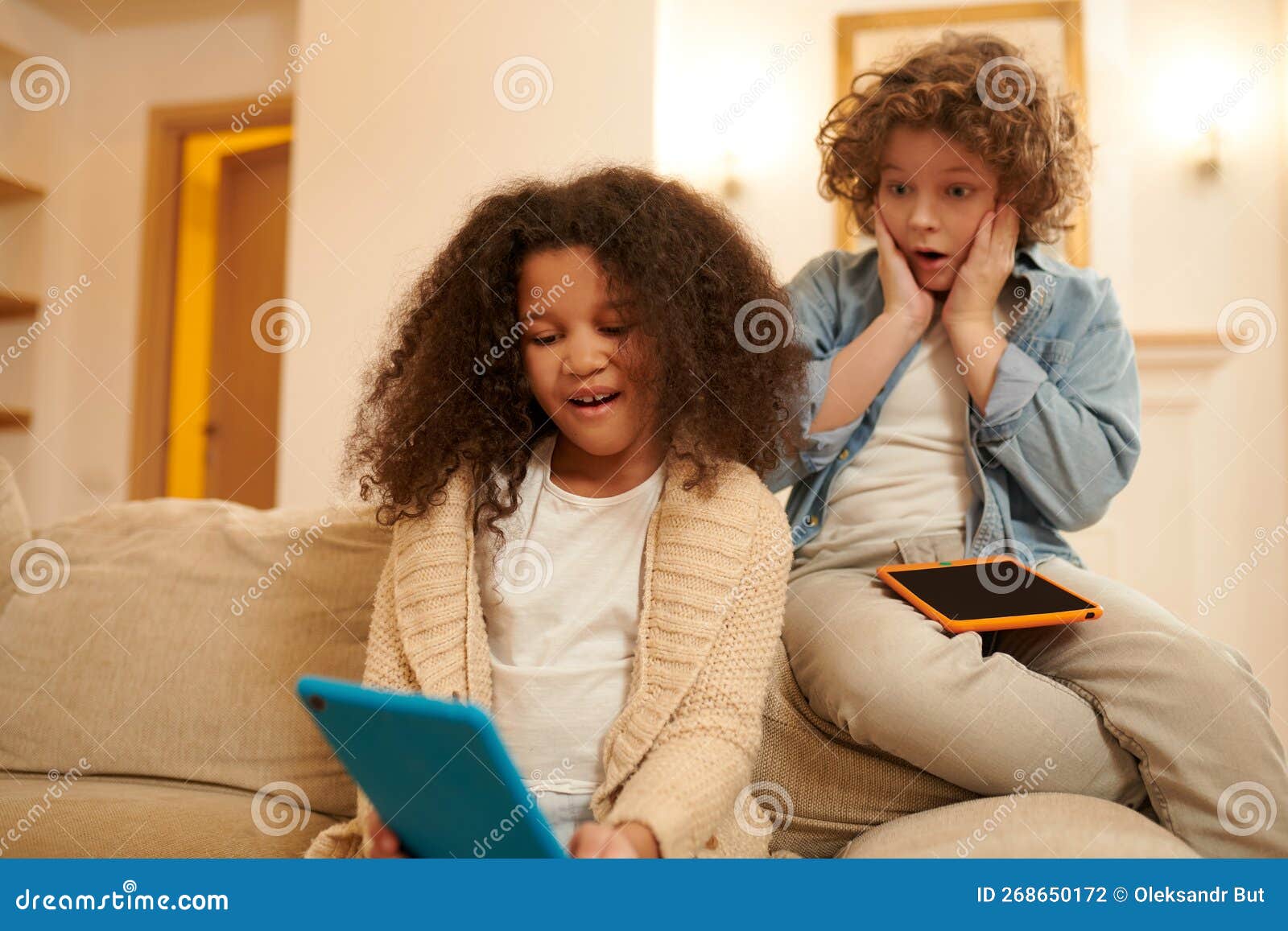 A Boy and a Girl with Devices Watching Something Online Stock Photo ...
