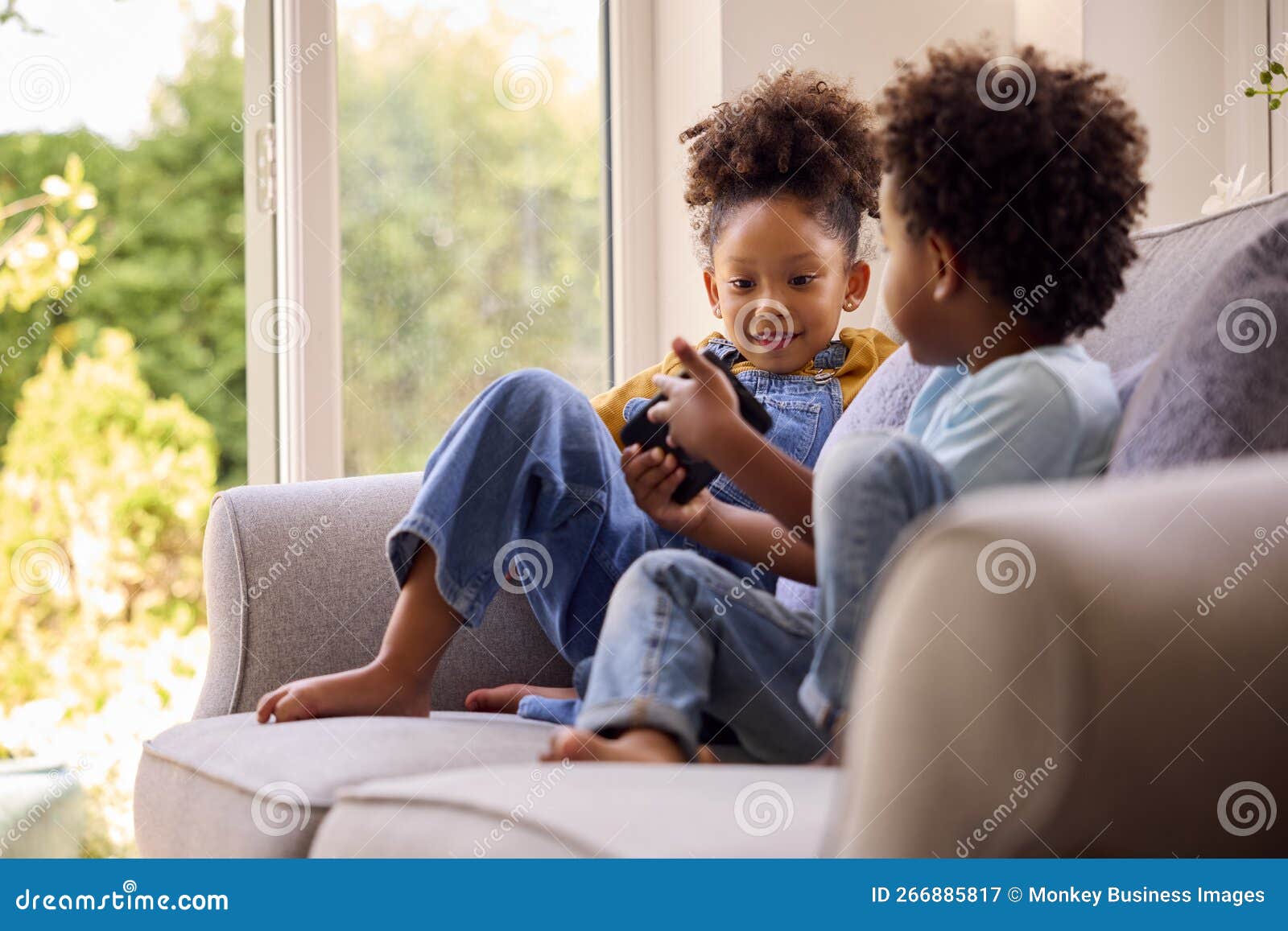 Boy and Girl Playing Handheld Computer Game Sitting on Sofa at Home ...