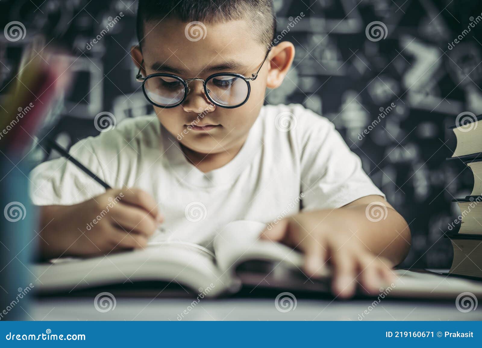 A Boy with Glasses Man Writing in the Classroom Stock Image - Image of ...