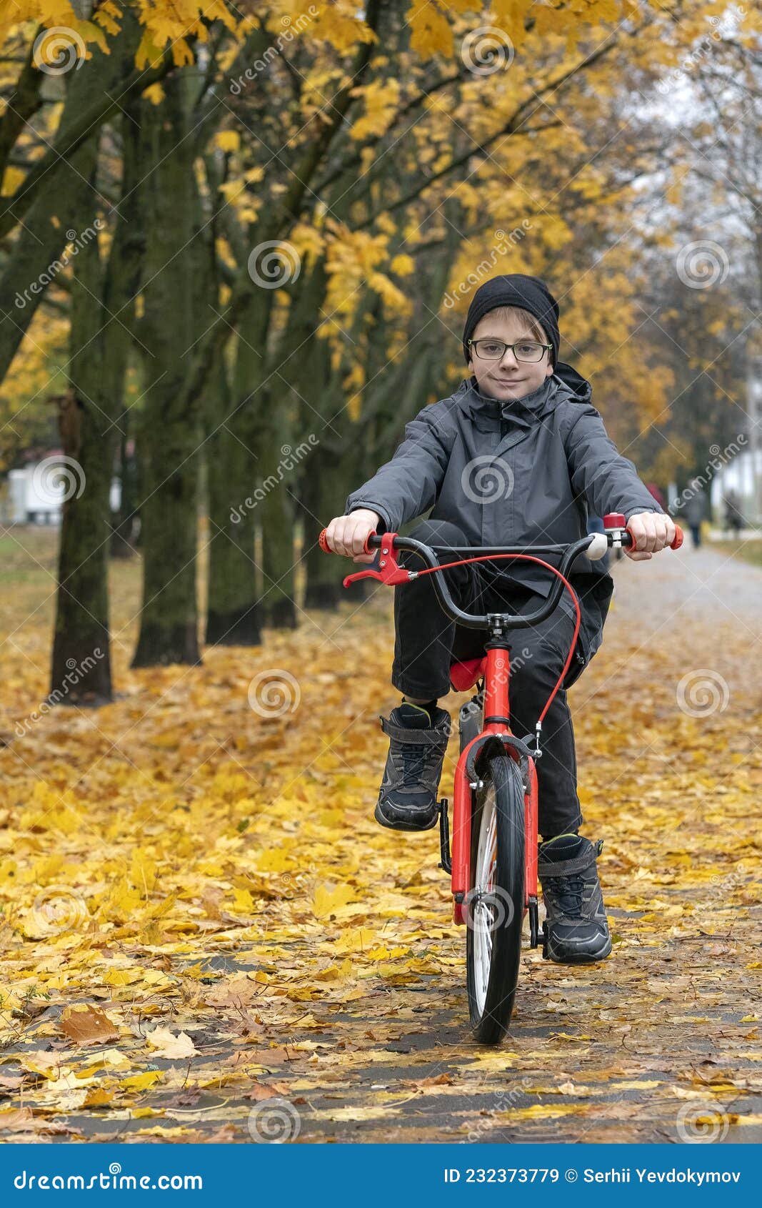 Boy with Glasses Rides Bicycle in the Autumn Park and Looking at Camera ...
