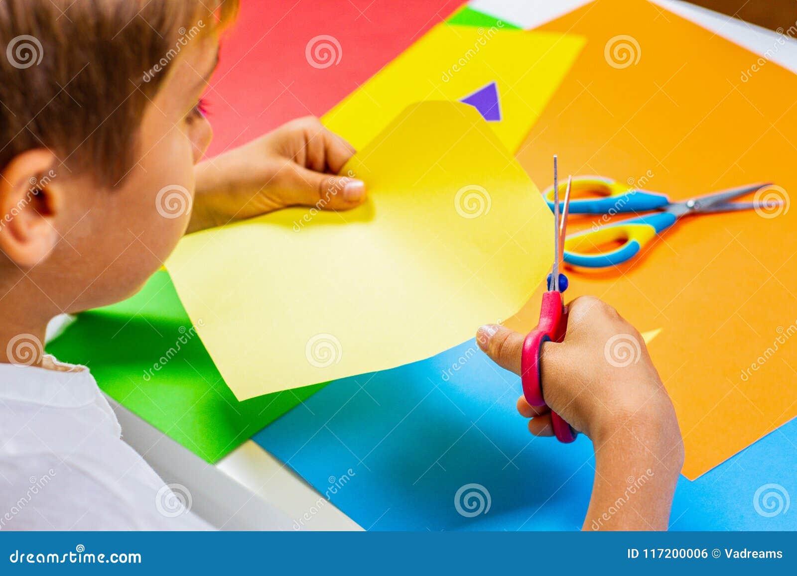 Child Cutting Colored Paper with Scissors at the Table Stock Photo ...