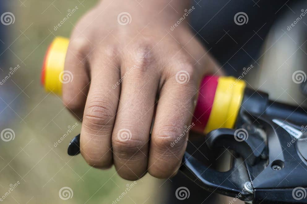 A Boy is Holding the Handle of a Bicycle and the Background is Blurred ...