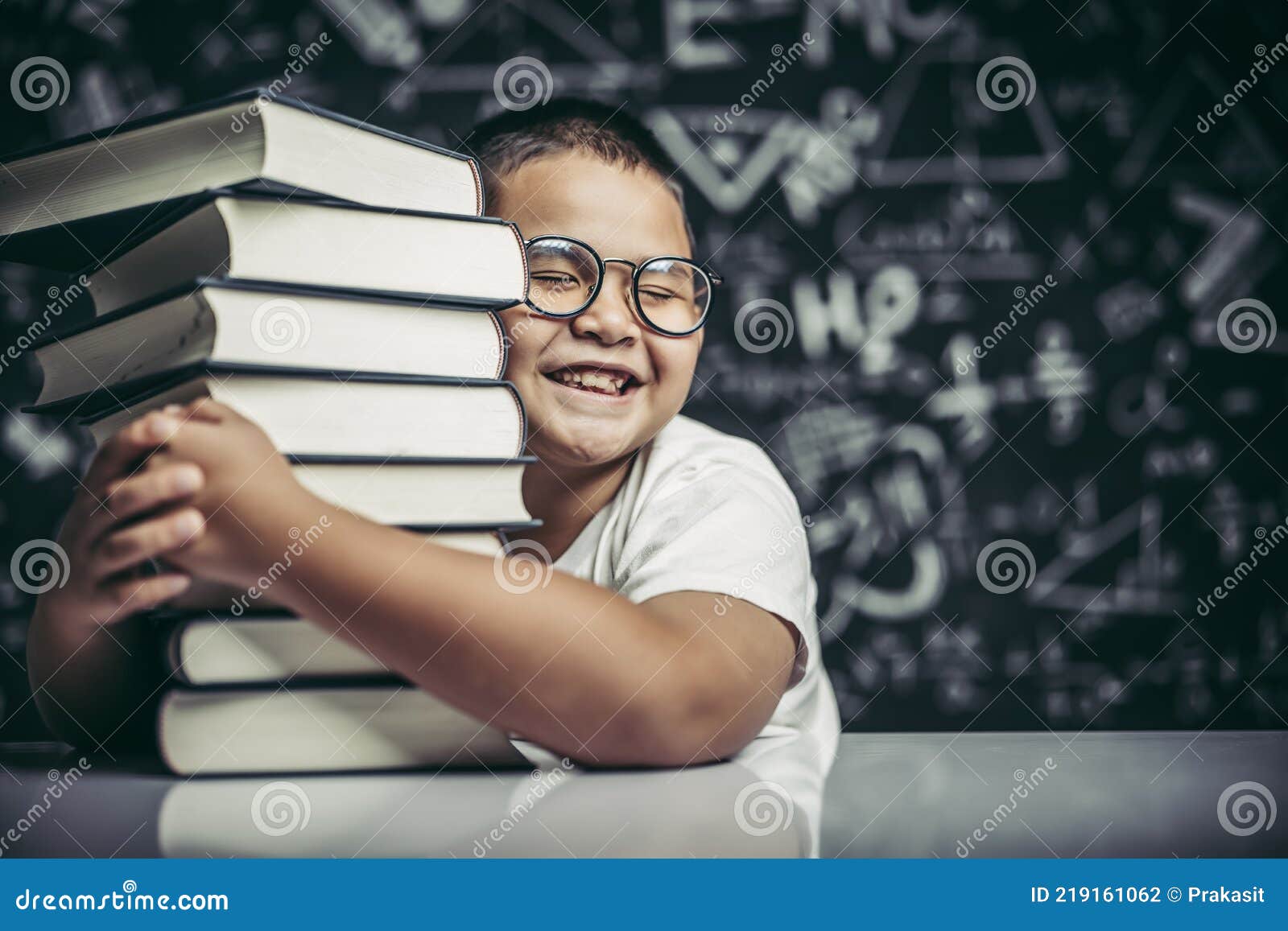 A Boy Hugging a Pile of Books Stock Photo - Image of book, male: 219161062