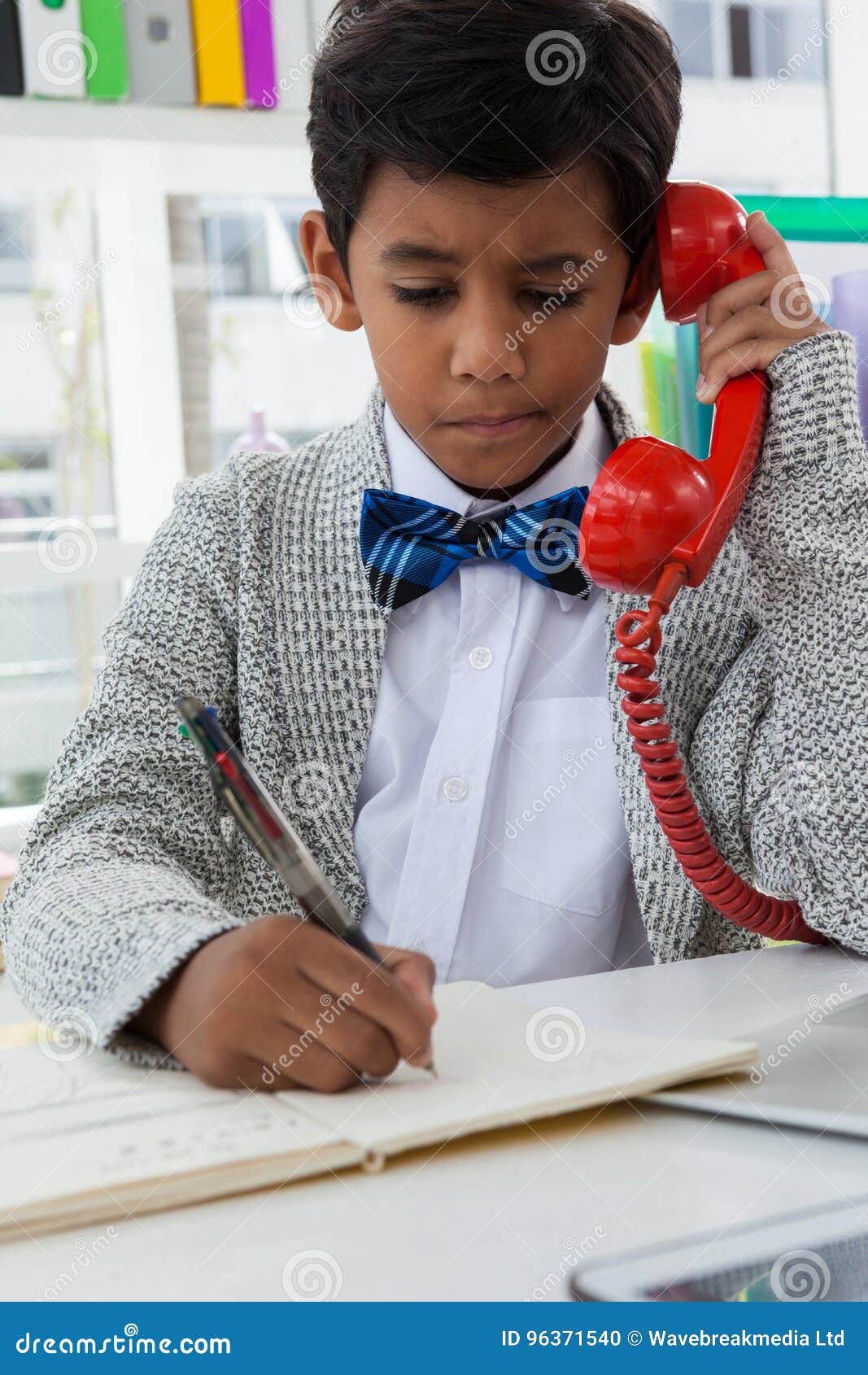 Boy Imitating As Businessman Writing on Book while Using Landline Stock ...
