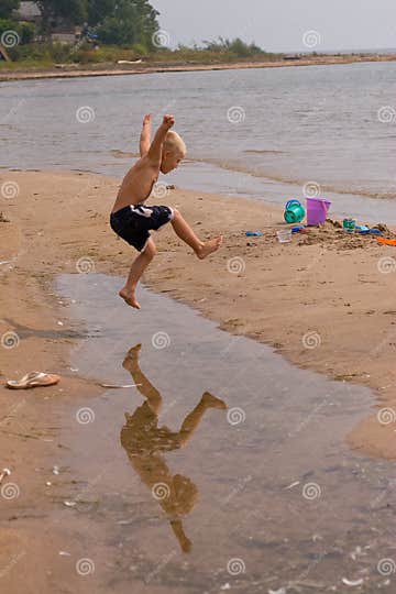 Boy jumping over puddle stock image. Image of happy, jumping - 6622733