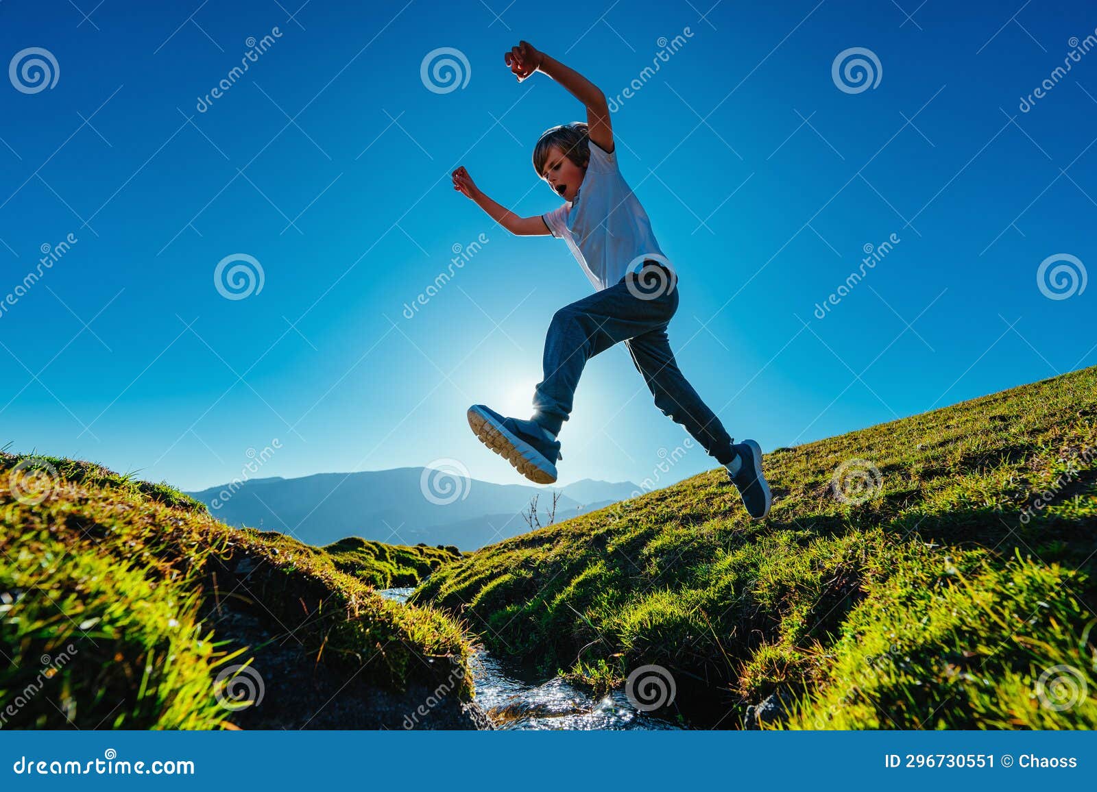 Boy Jumping Over Stream in the Mountains Stock Image - Image of ...