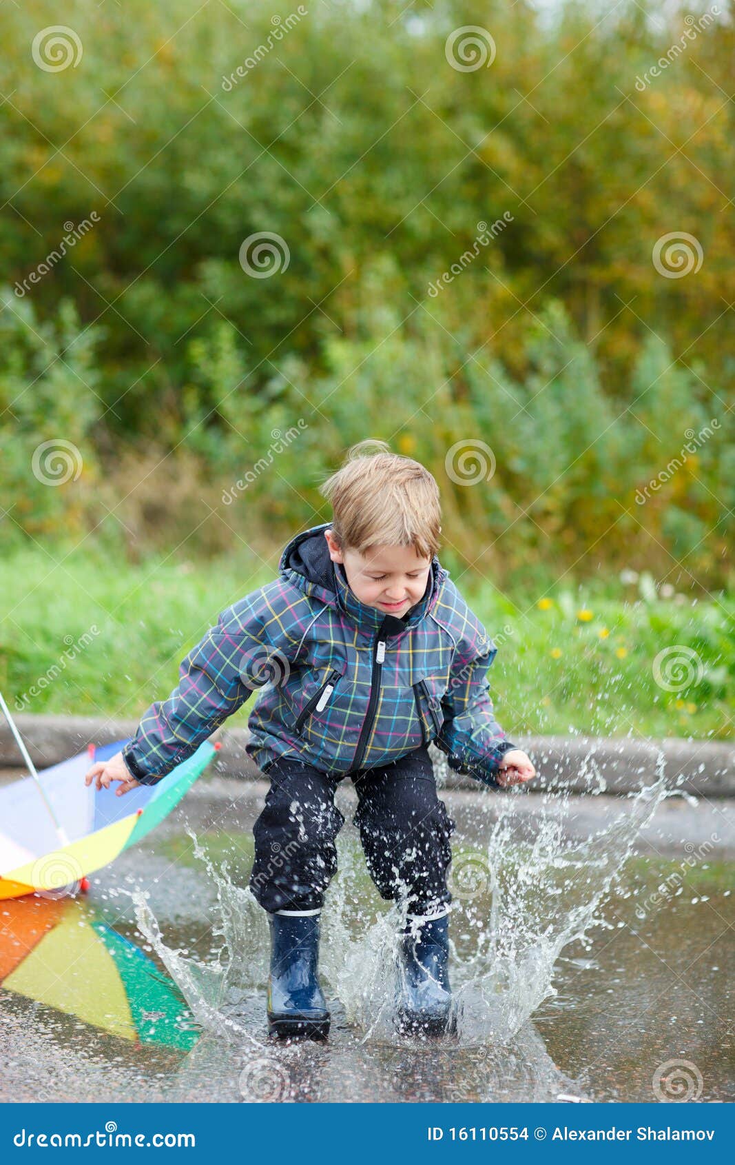 Boy jumping in puddle stock photo. Image of jacket, boot - 16110554