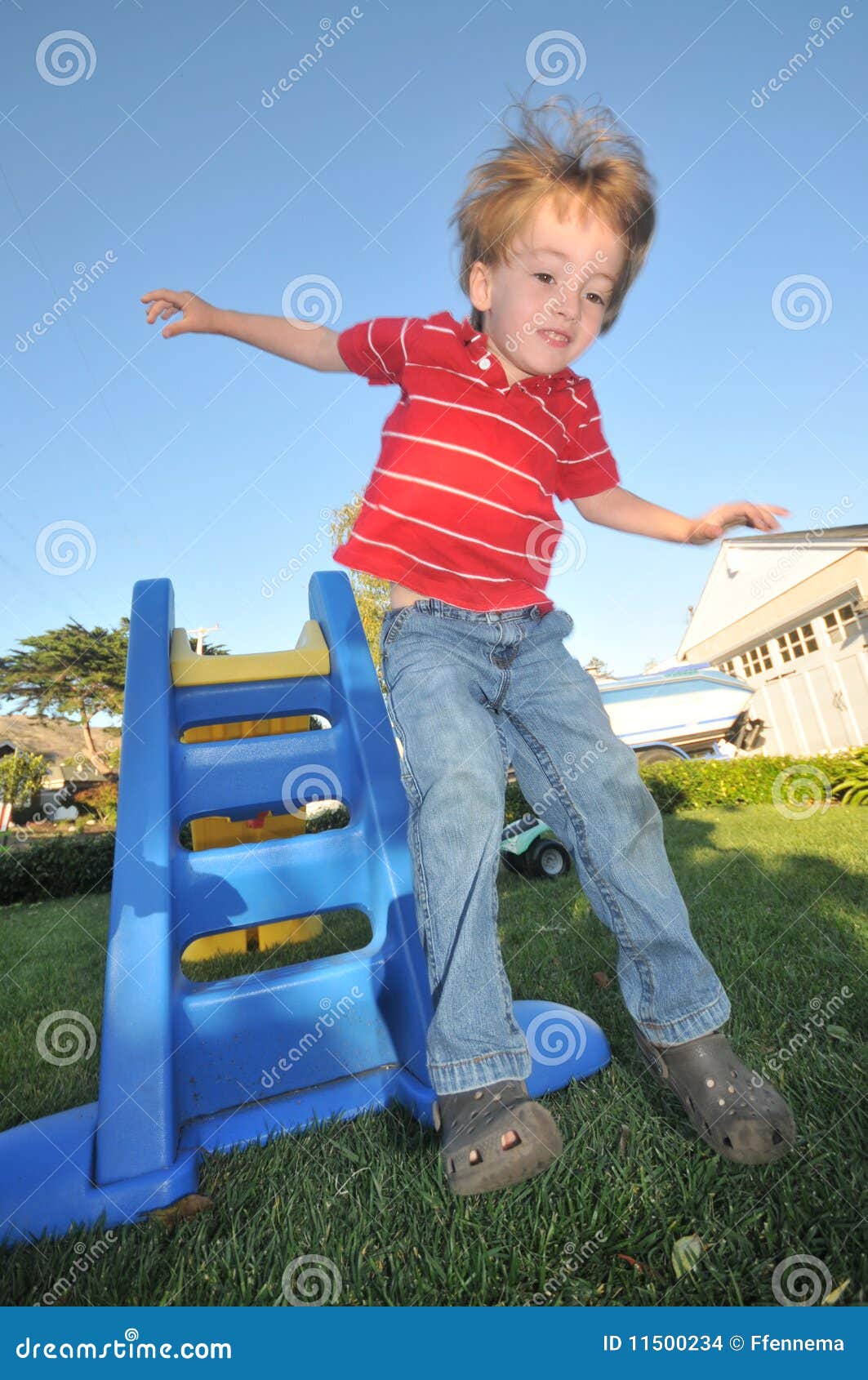 Boy Jumps Off a Slide Onto the Grass Stock Photo - Image of slide ...