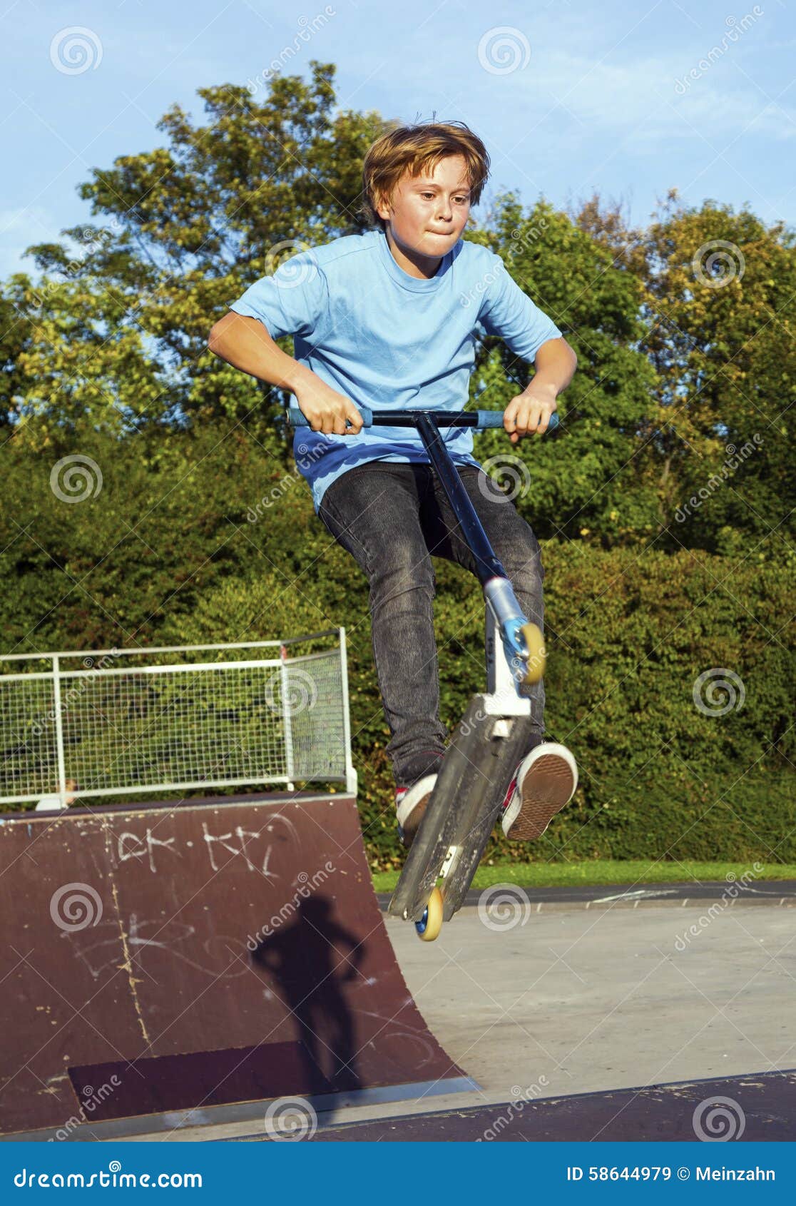 Boy Jumps with Scooter at the Skate Park Over a Ramp Stock Image ...