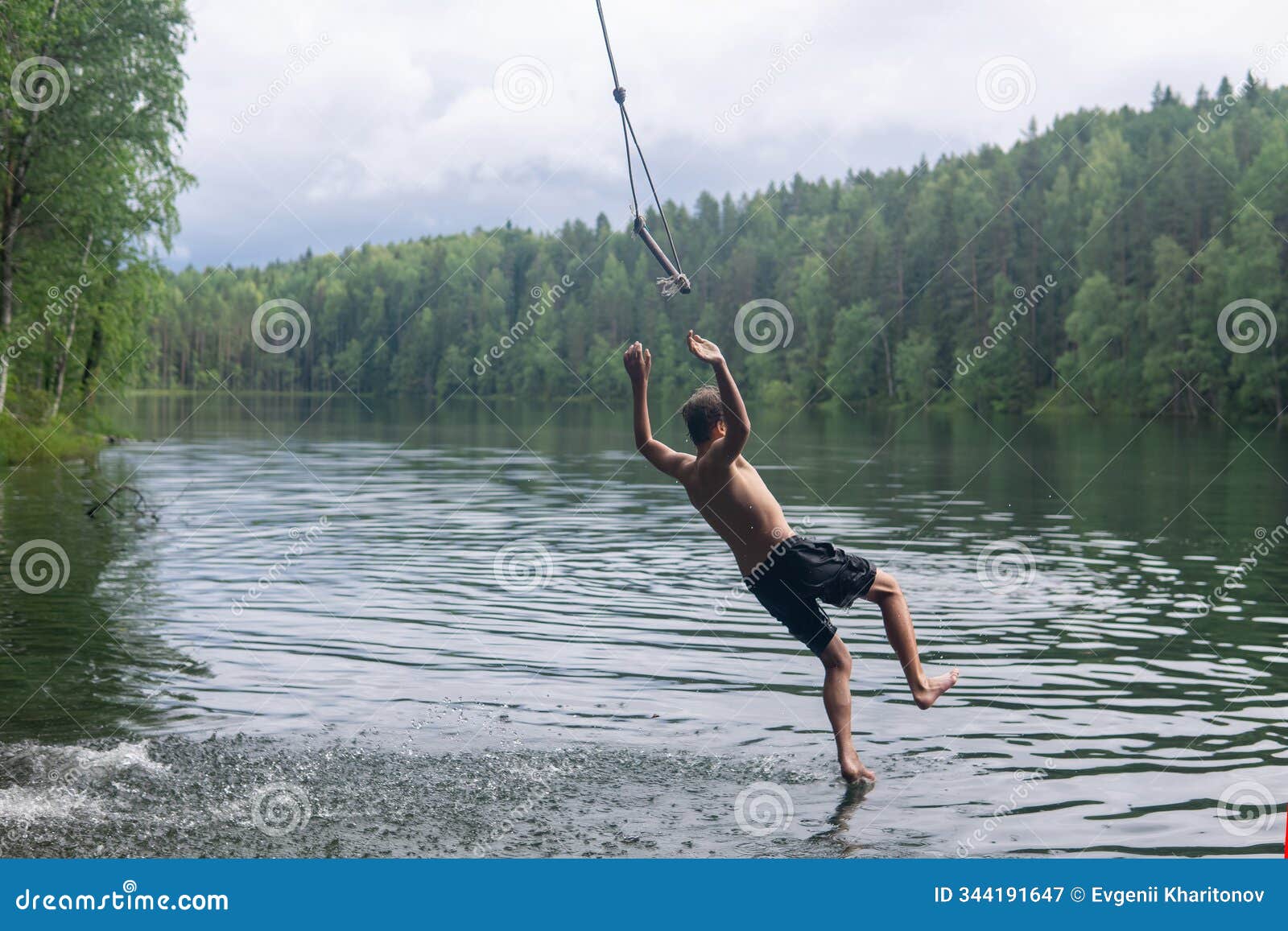 Boy Jumps into the Water Using a Tarzan Swing while Swimming in a ...