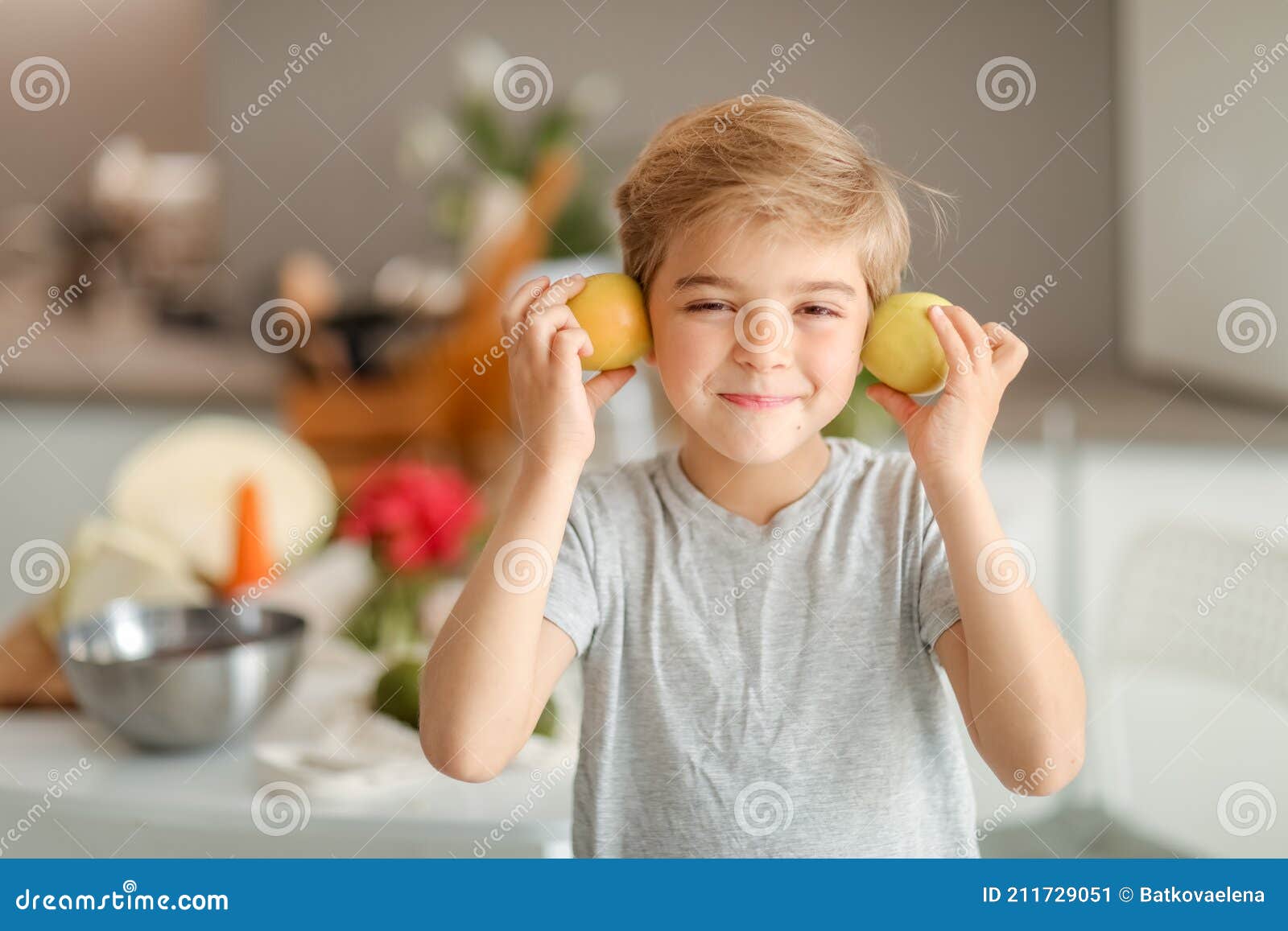 The Boy in the Kitchen is Amused and Fooled Around with Two Apples in ...