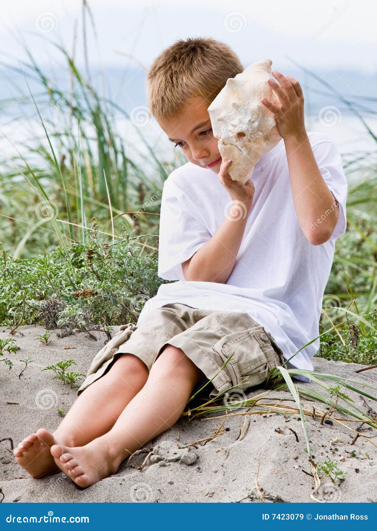 Boy Listening To Seashell at Beach Stock Image - Image of coastline ...