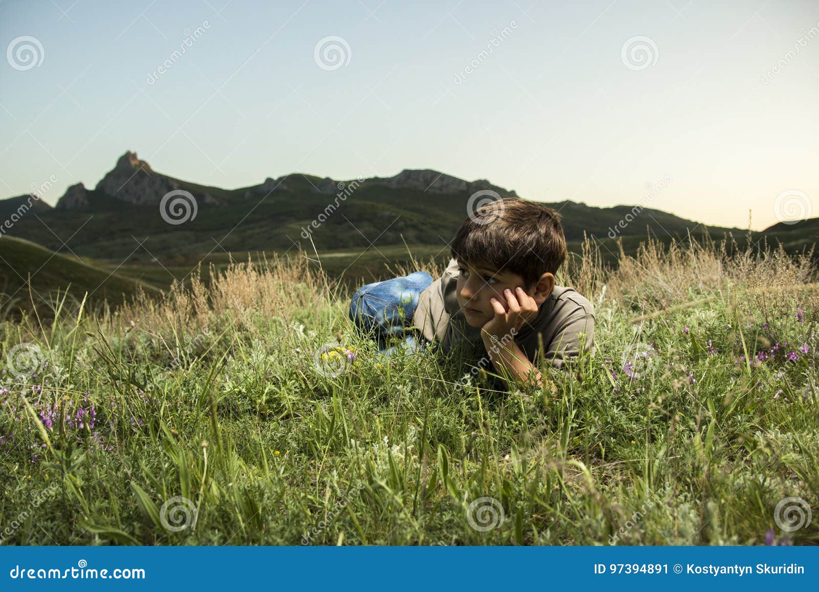 Boy Lying in Grass at Backdrop of the Mountains Stock Image - Image of ...
