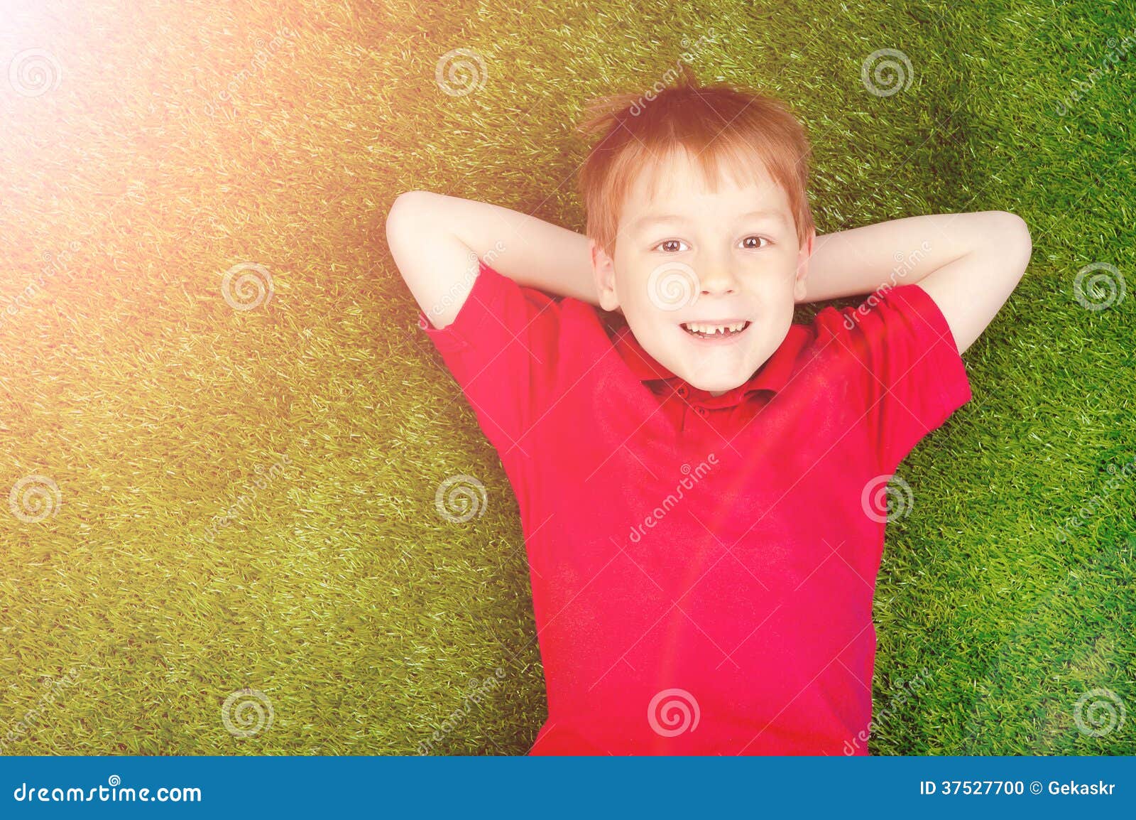 Boy lying on a green lawn stock photo. Image of happiness - 37527700