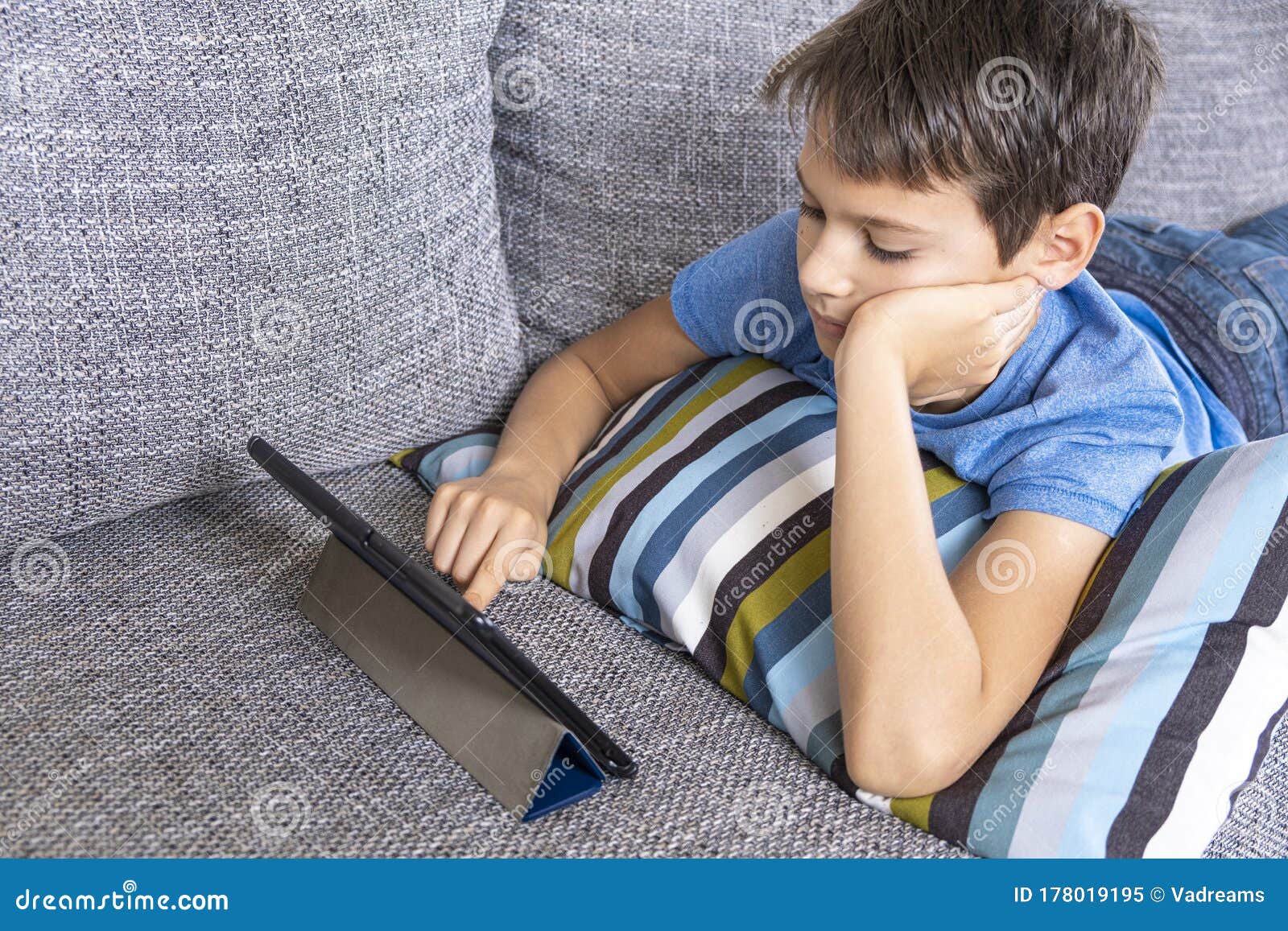 Boy Lying on Sofa with Digital Tablet Computer at Home. Technology ...