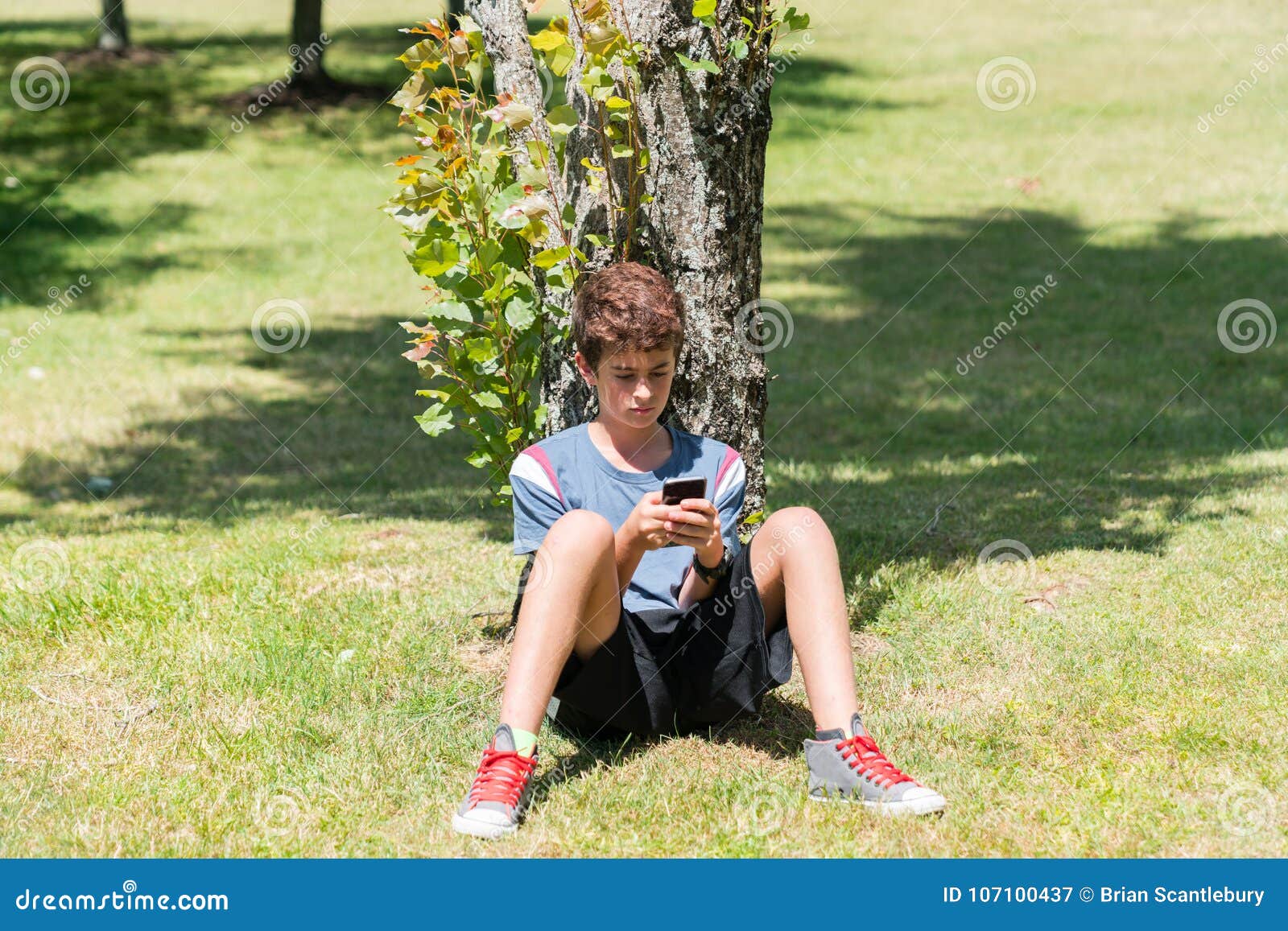 Boy with mobile in garden stock image. Image of device - 107100437