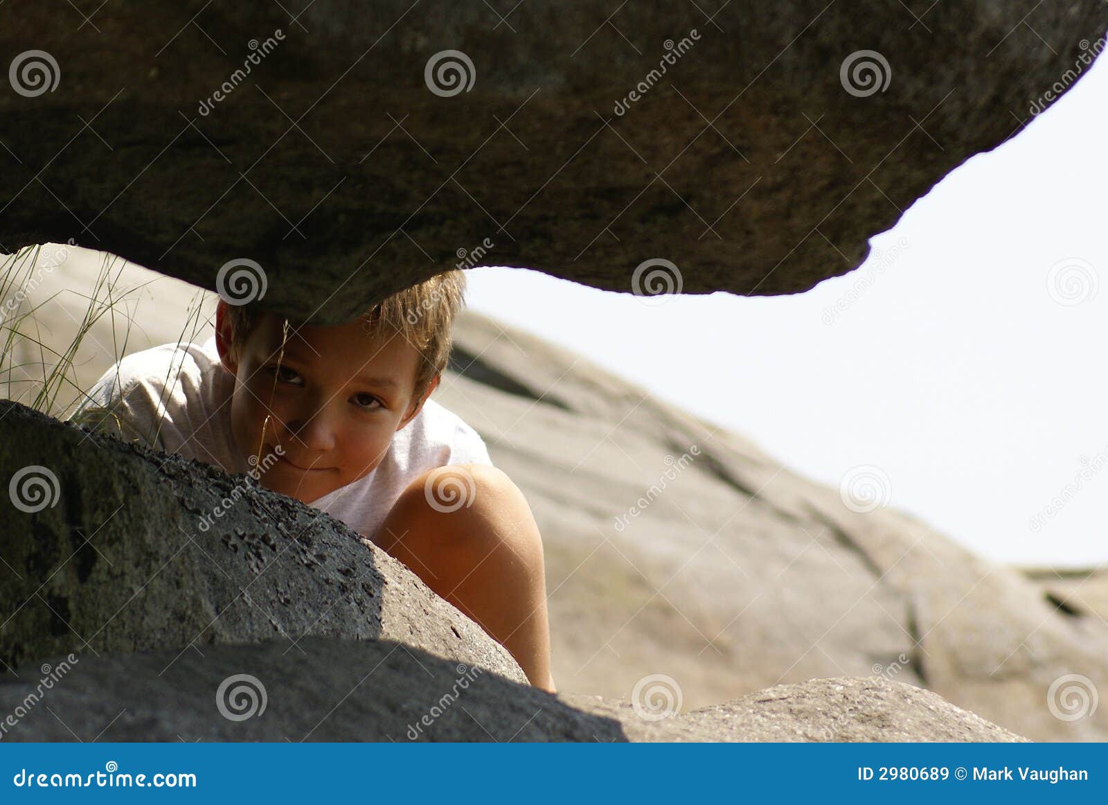 A Boy Peering between Rocks Stock Image - Image of peering, innocence ...