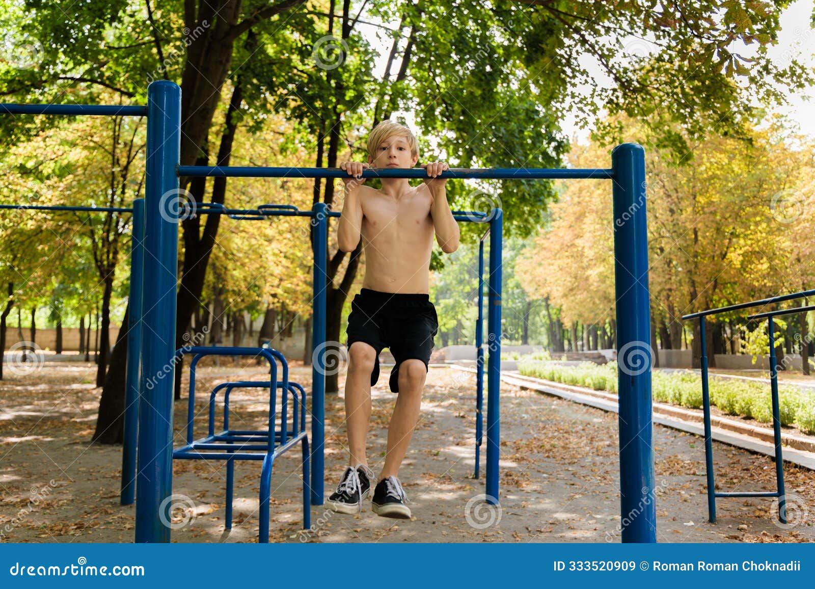 A Boy Performs Pull-ups in the Park. Athletic Teenage Boy in the Park ...
