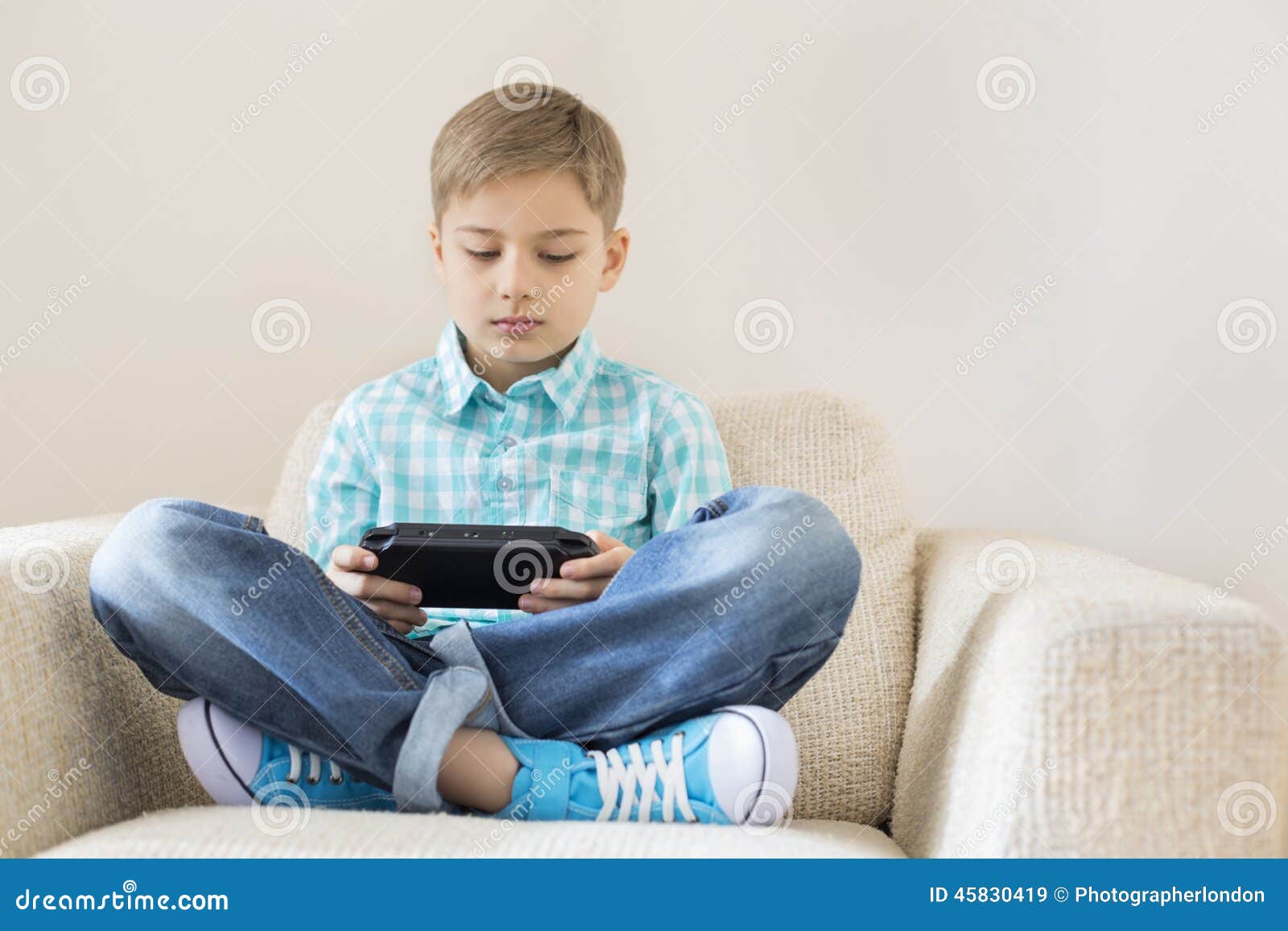 Boy Playing Hand-held Video Game on Sofa Stock Image - Image of ...