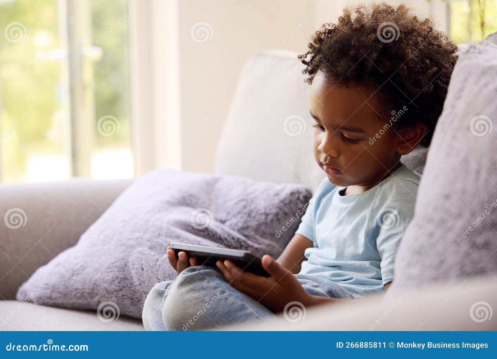 Boy Playing Handheld Computer Game Sitting on Sofa at Home Stock Image ...