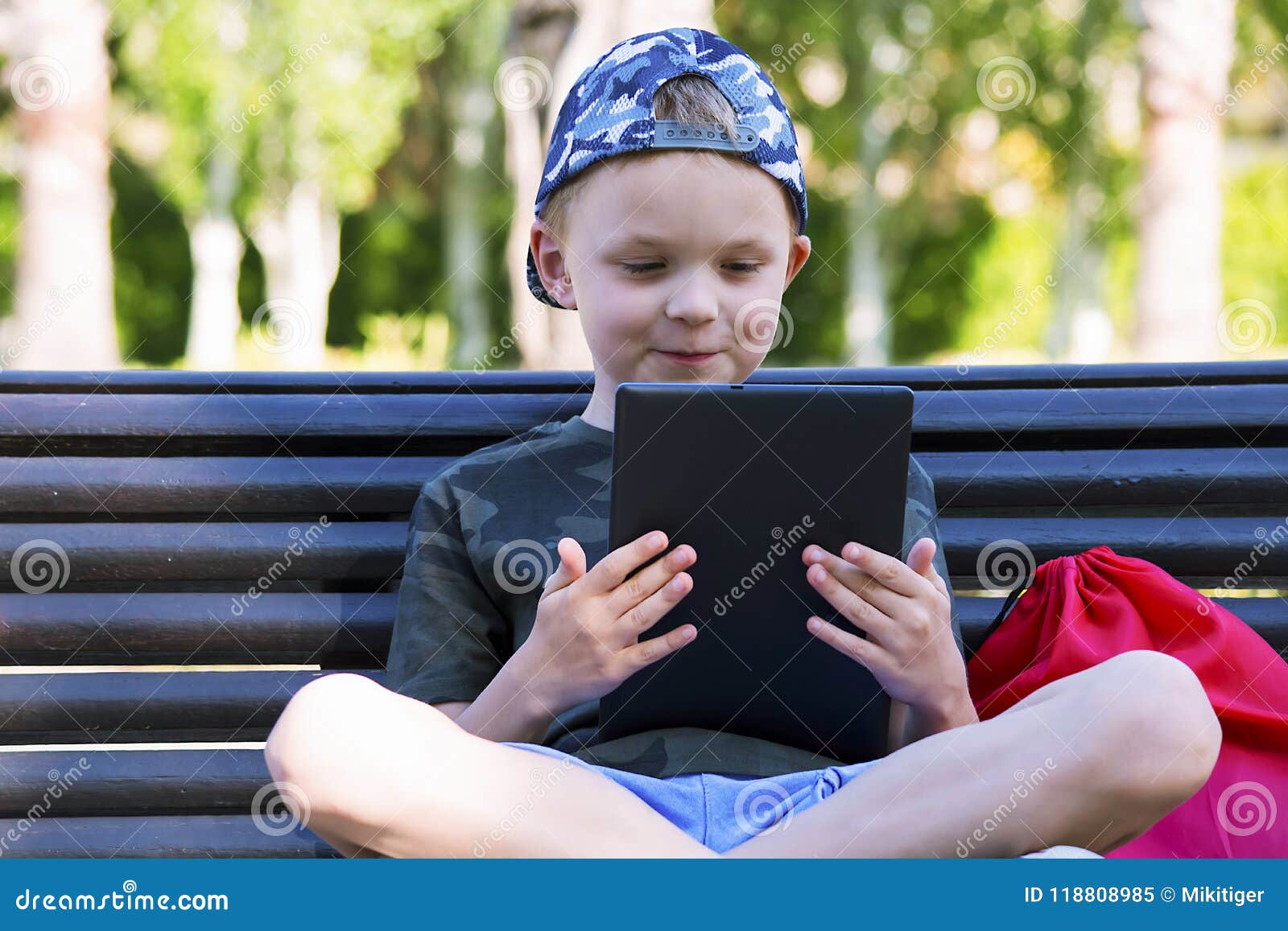 Boy is Playing in the Tablet on a Bench Stock Image - Image of street ...
