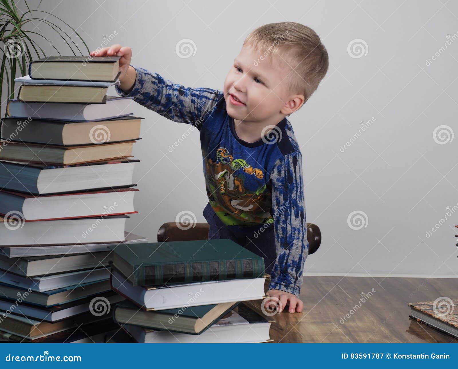 The Boy Reaches for the Stack of Books Stock Image - Image of person ...