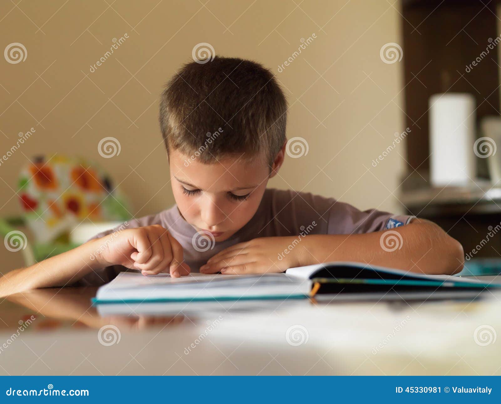 Boy Reading a Book while Sitting at Table at Home. Stock Image - Image ...