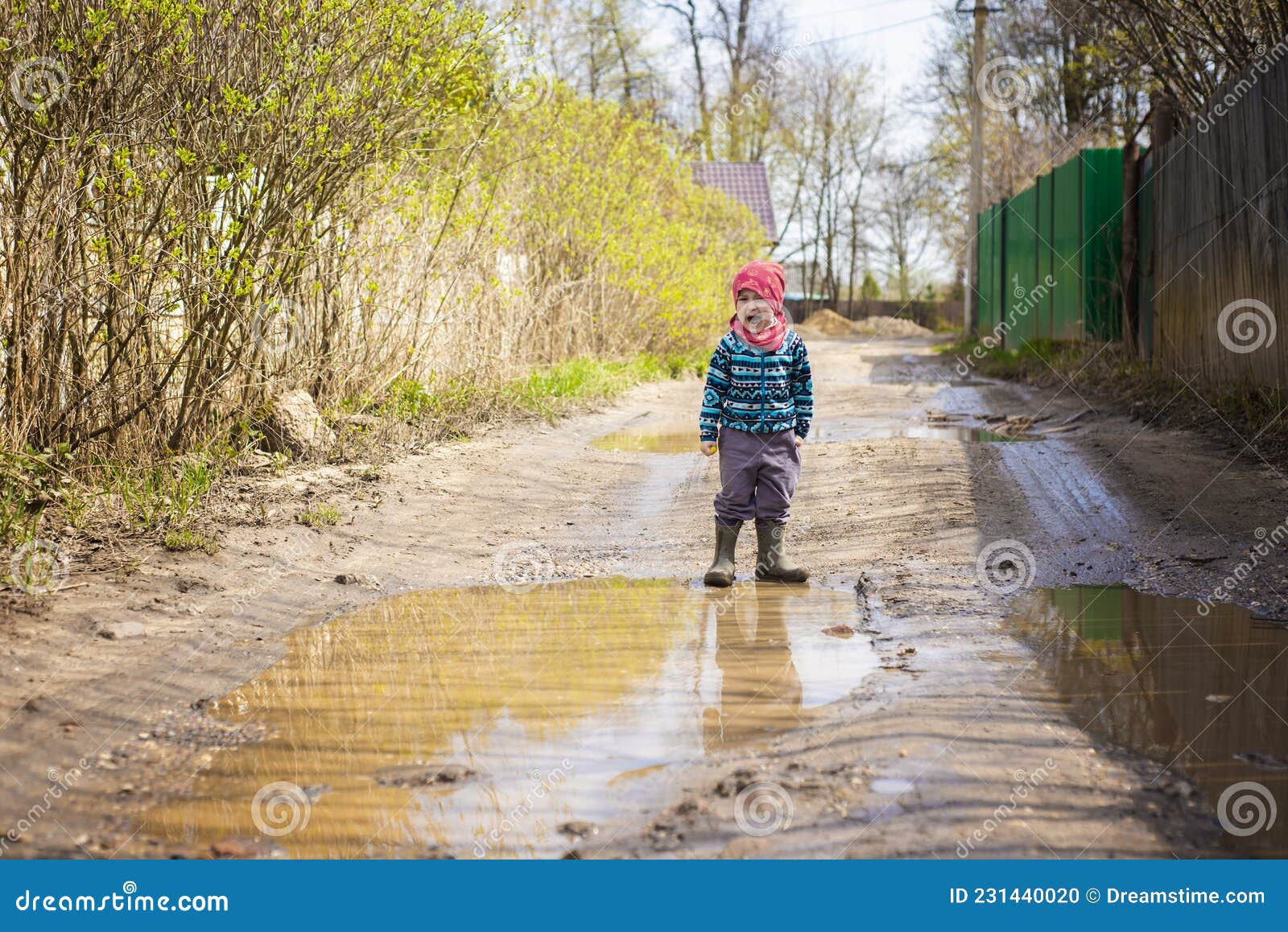 A Boy in a Red Hat and Rubber Boots Crying, Afraid of Puddles, Jumps ...