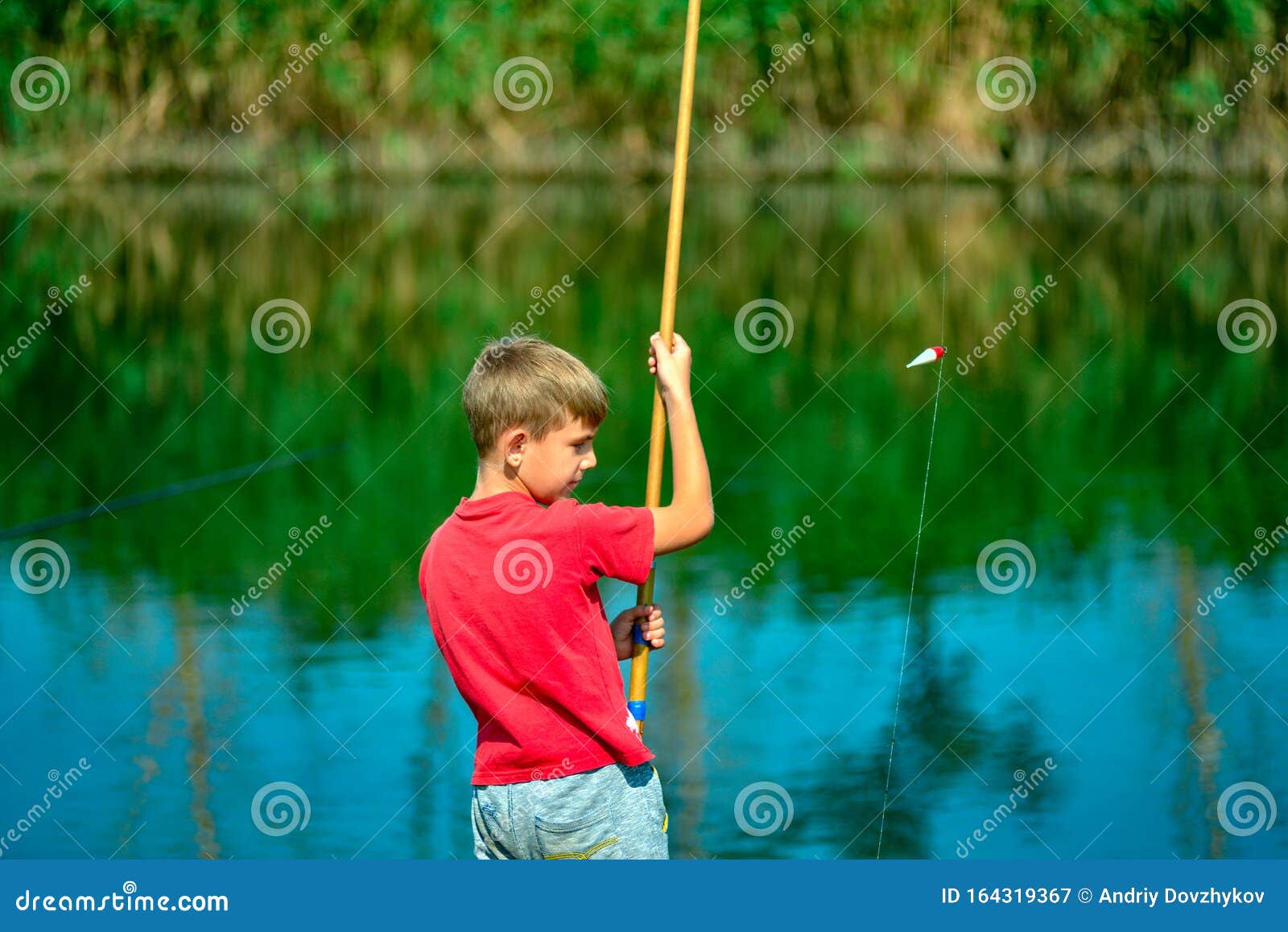A Boy in a Red Shirt Throws a Fishing Rod on the Catch River Stock ...
