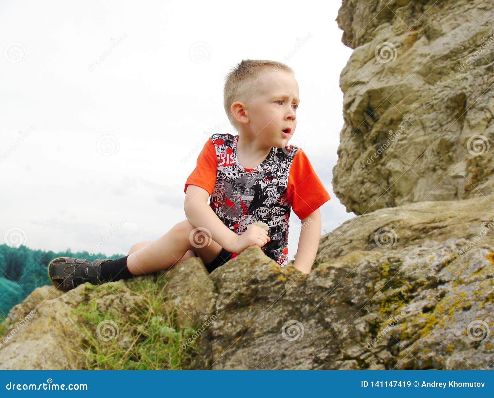 The boy on the rock. stock image. Image of cliff, blond - 141147419