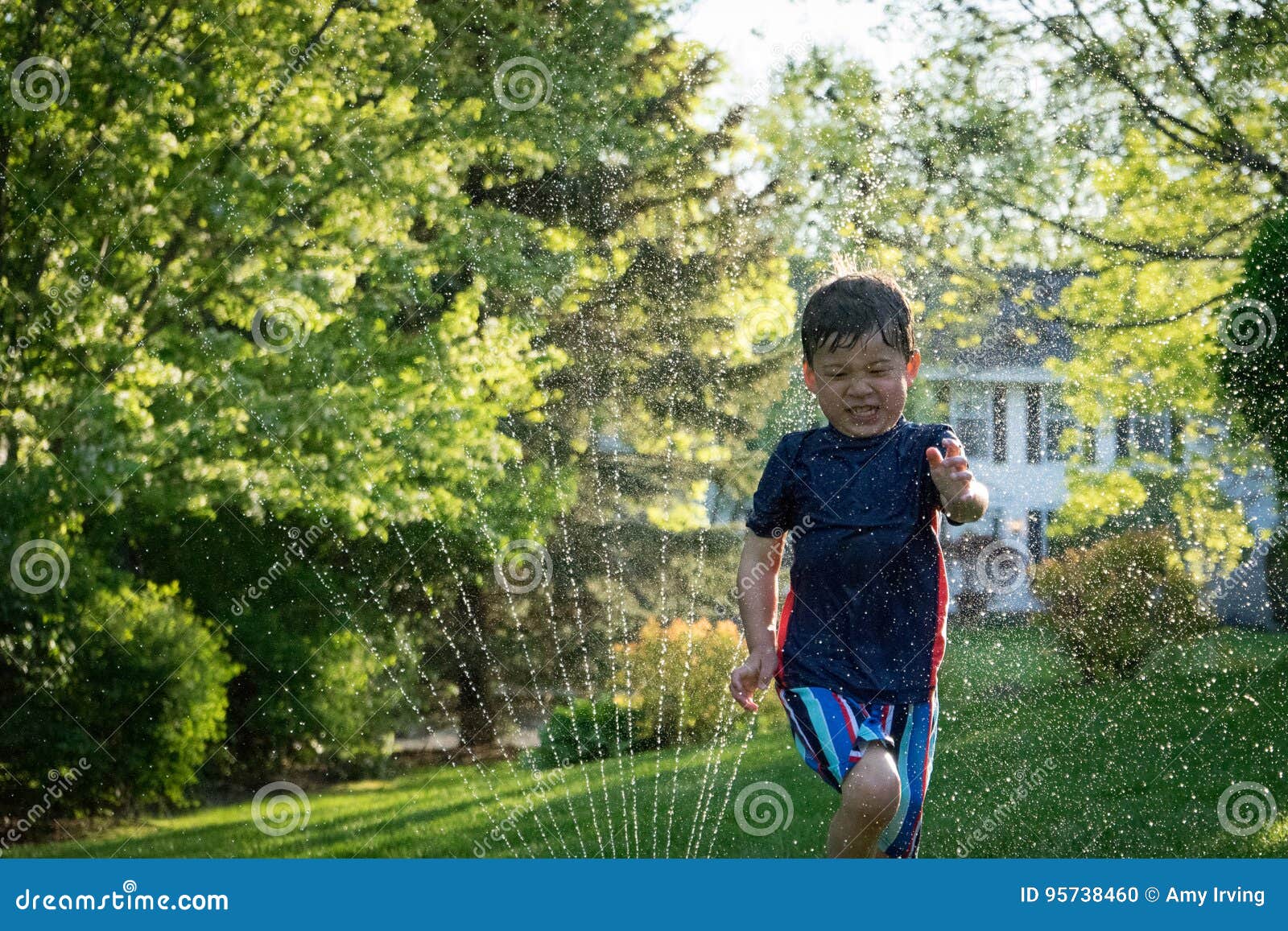 Boy Running through Sprinklers in Backyard Stock Photo - Image of ...