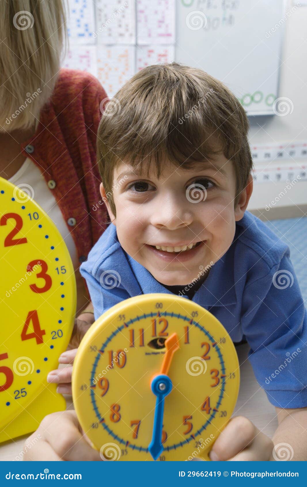 Boy Showing Yellow Clock With Teacher In Background Royalty-Free Stock ...