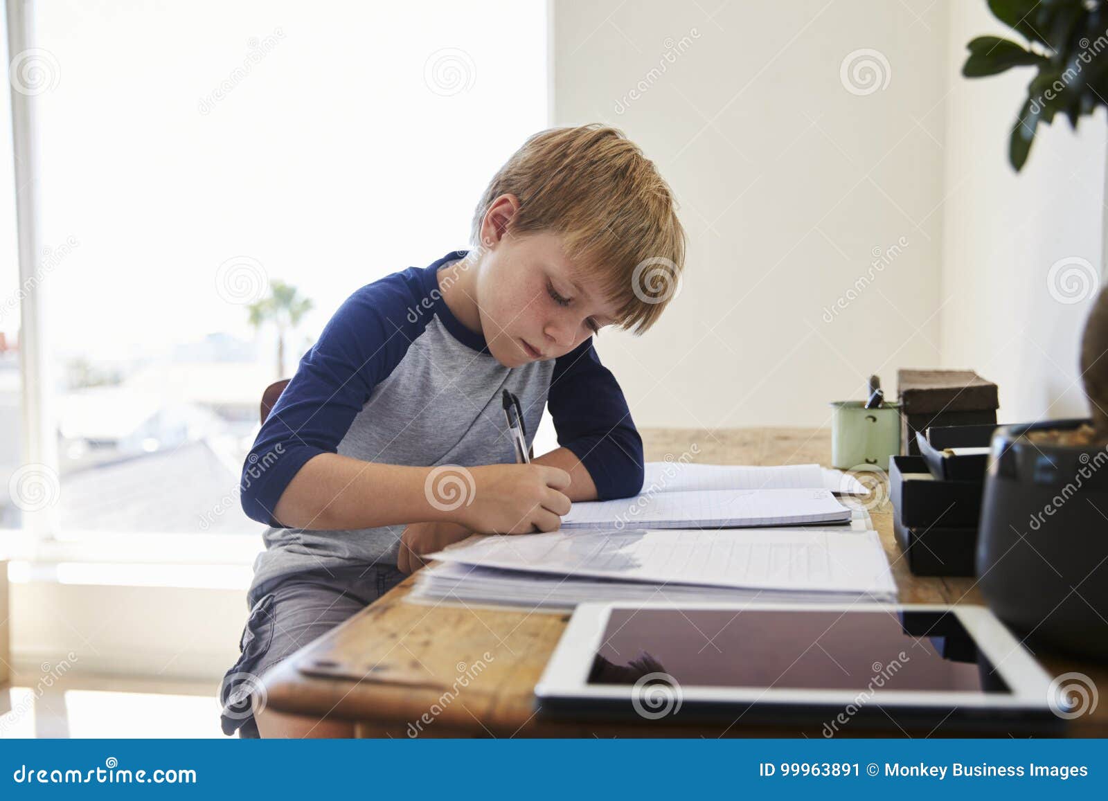 Boy Sits at Desk in Bedroom with Digital Tablet Doing Homework Stock ...