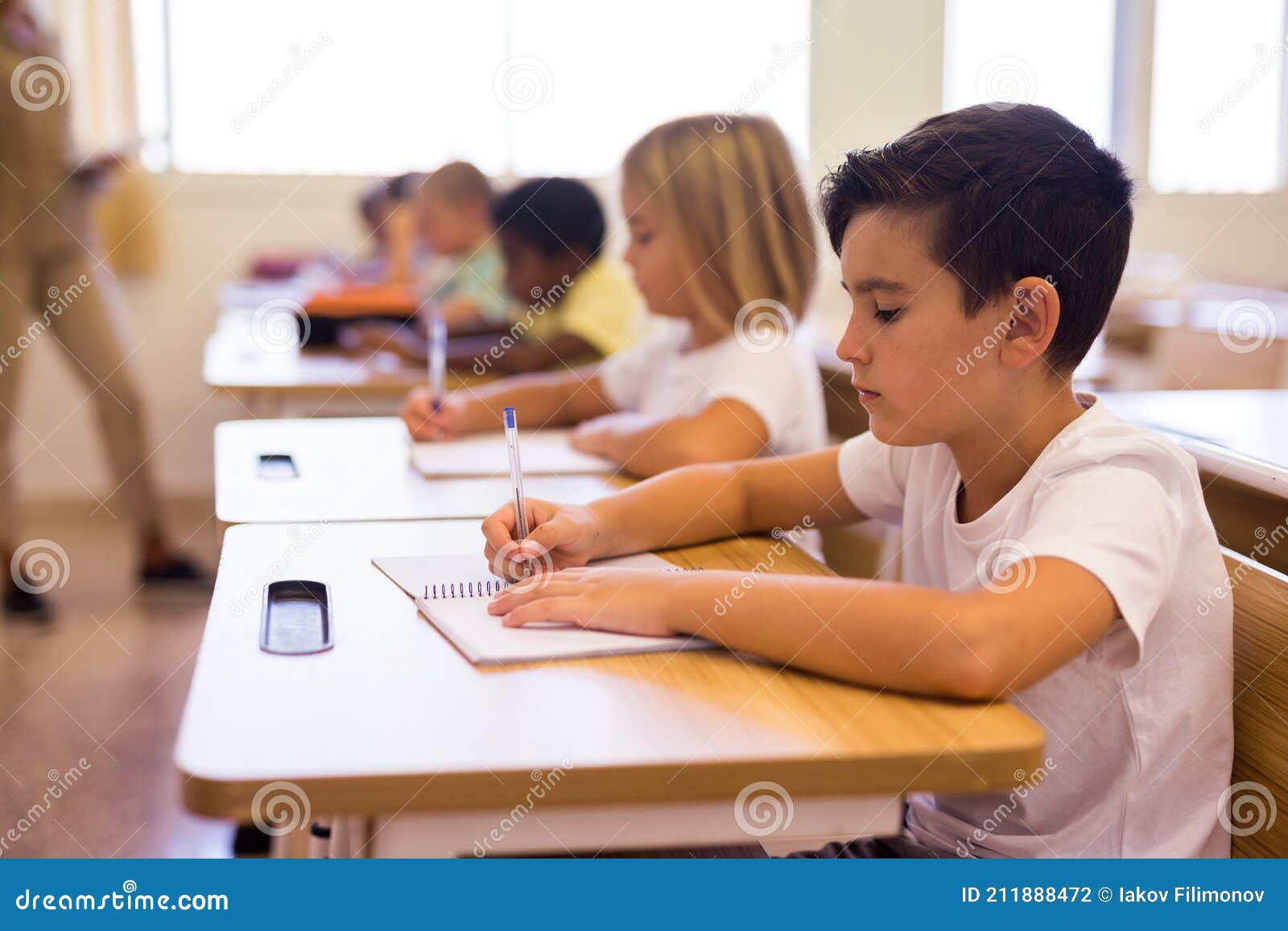 Boy Sits at Desk Next To Diligent Elementary School Students Stock ...