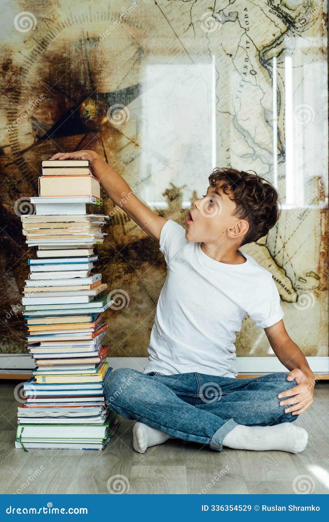 A Boy Sits Next To a Stack of Books and Holds Them with His Hand Stock ...