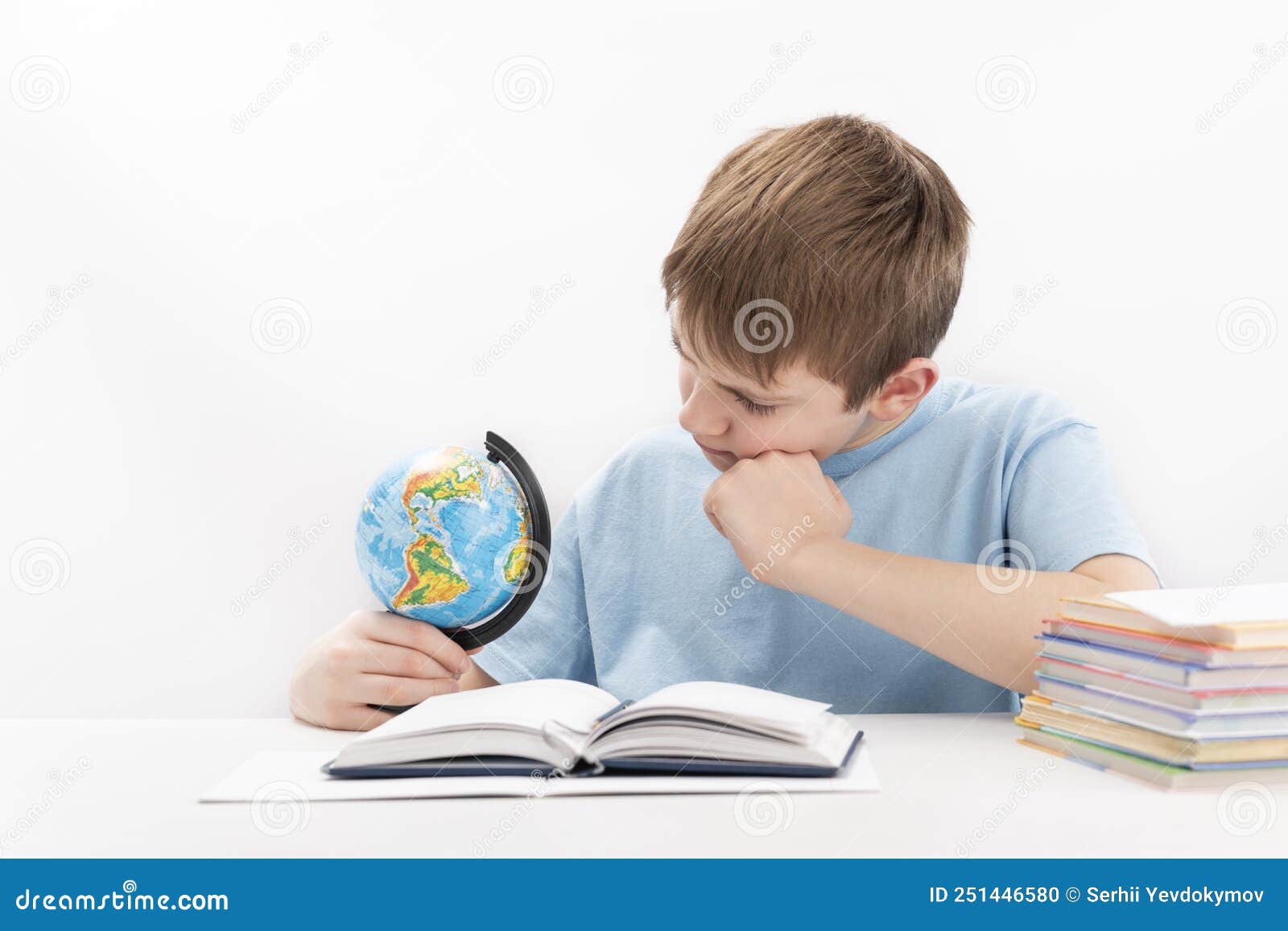 Boy Sits at Table with Globe in Hands and Thinks about Something ...